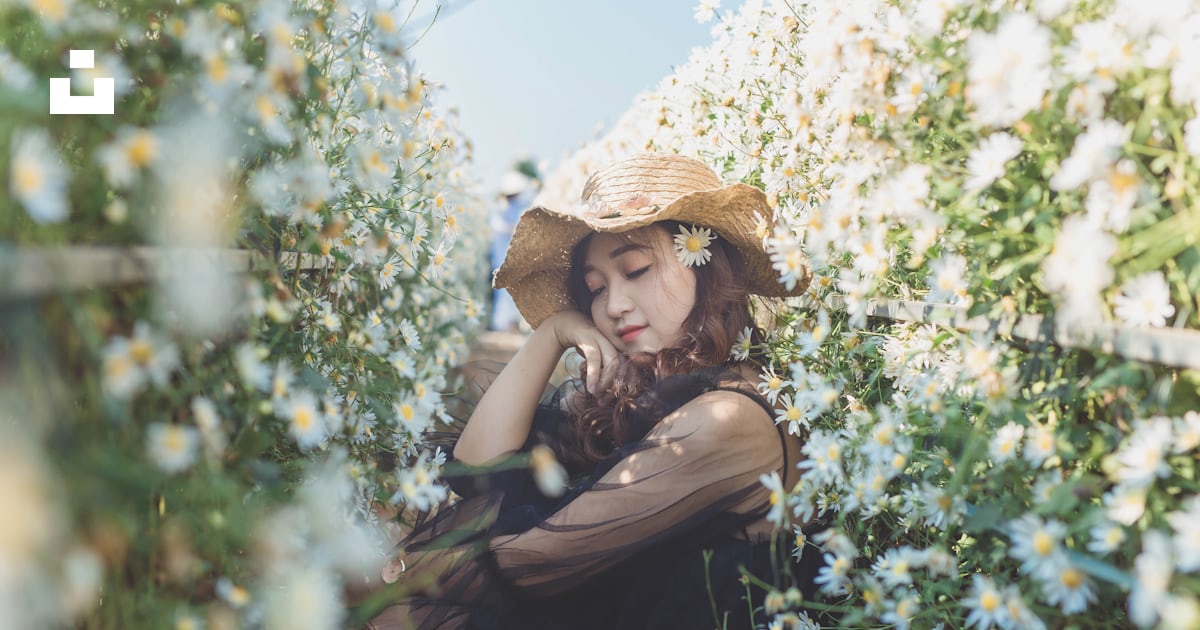 검은 드레스와 갈색 태양 모자를 쓴 여자는 낮 동안 푸른 잔디에 앉아 사진 Unsplash의 무료 꽃 이미지