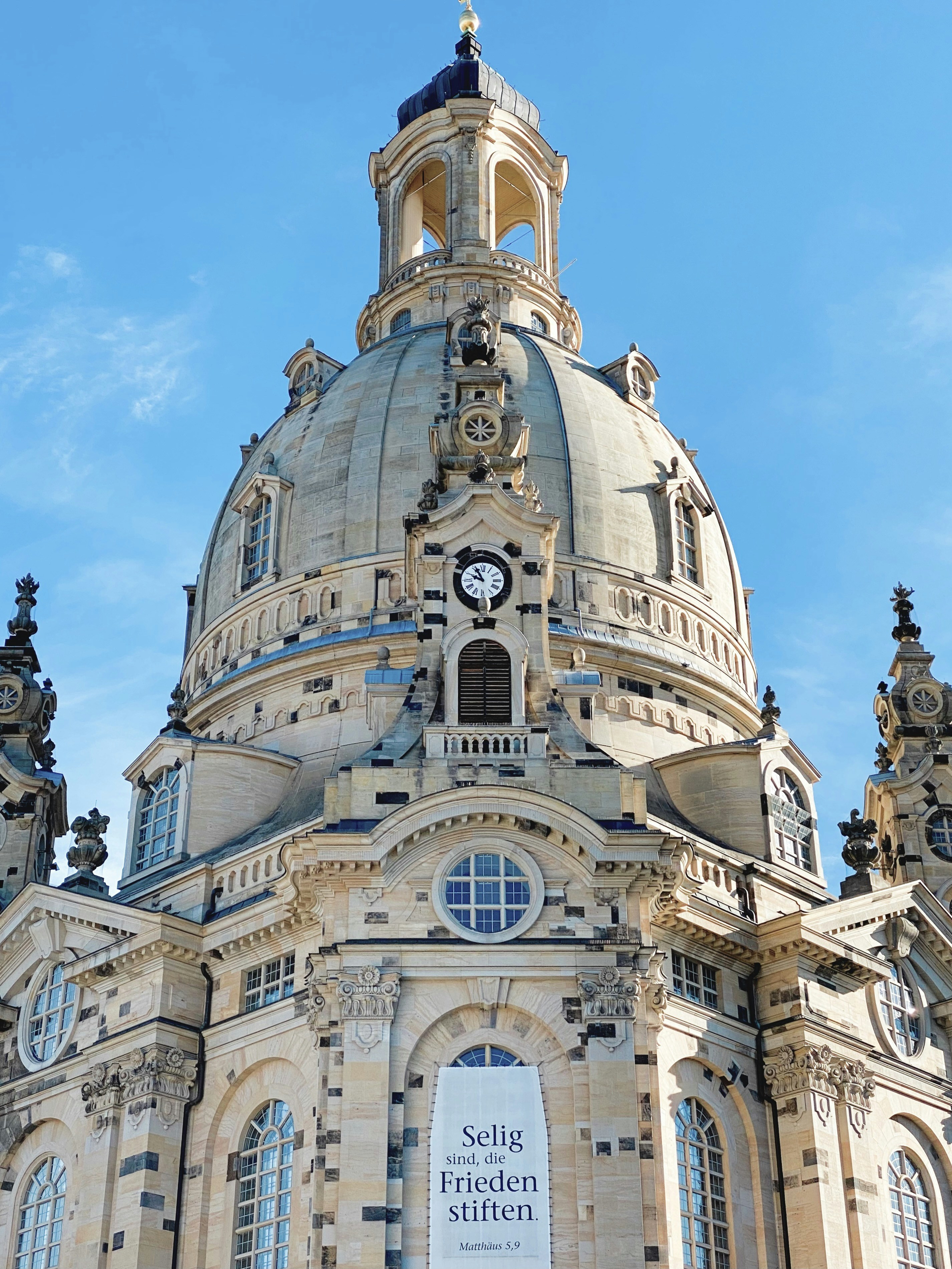 Sunlit Baroque Dome: Clock Facade Rising Against a Clear Blue Sky