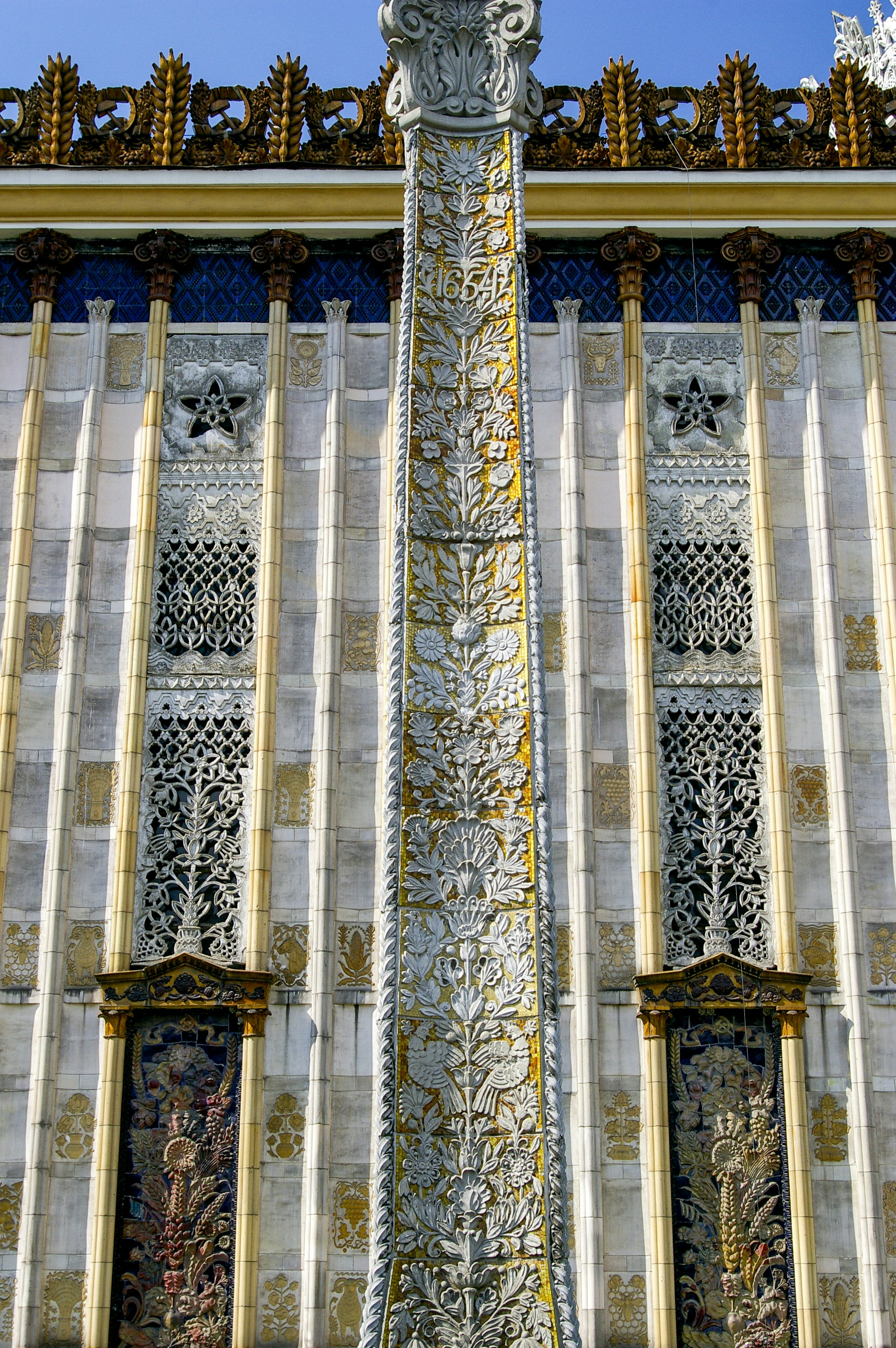 Laurel-Leaf Column Framing a Blue-and-Gold Temple Facade