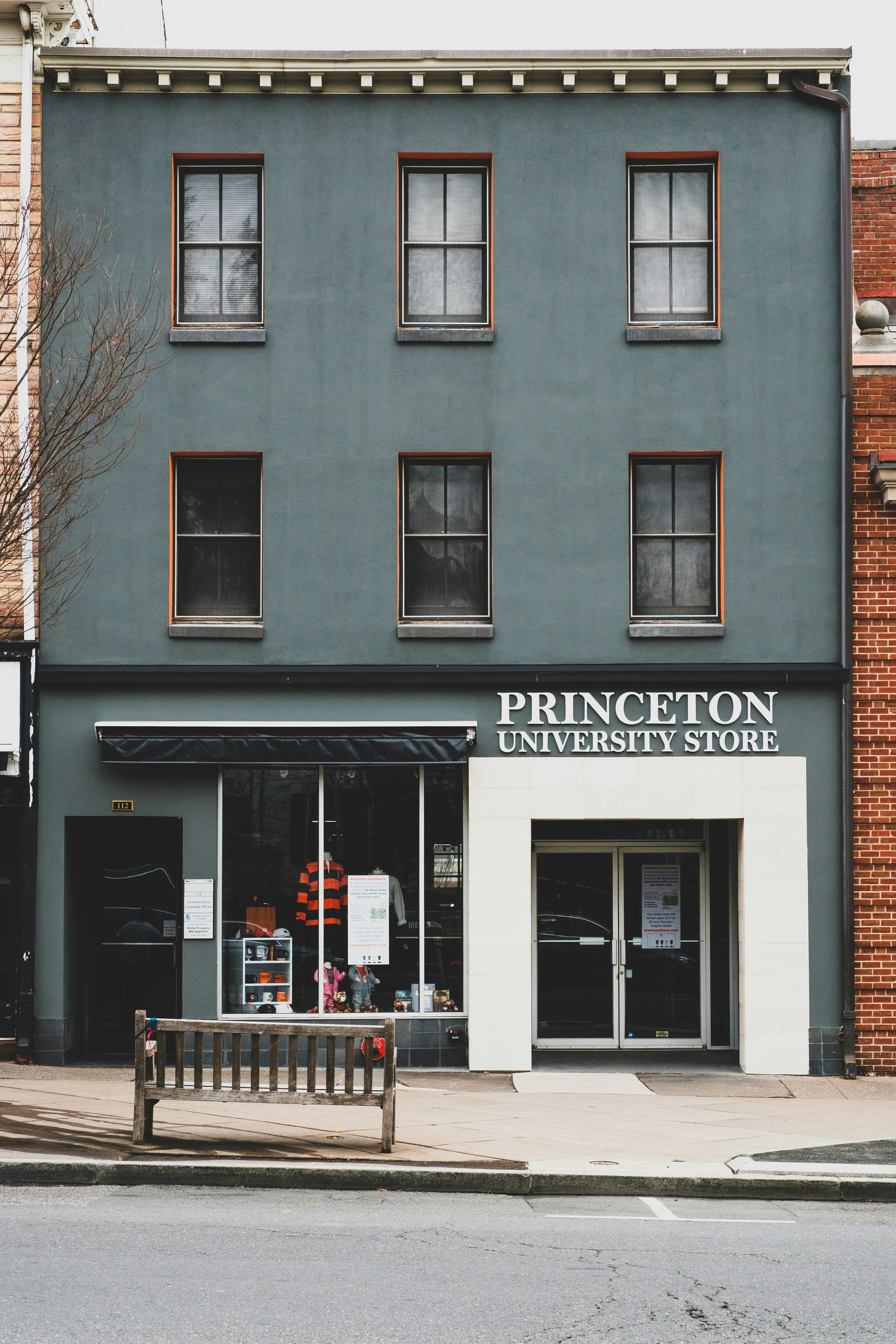 A university store featuring a modern facade with large windows, showcasing merchandise and a welcoming entrance. The building's muted colors and architectural details reflect a blend of tradition and contemporary style.