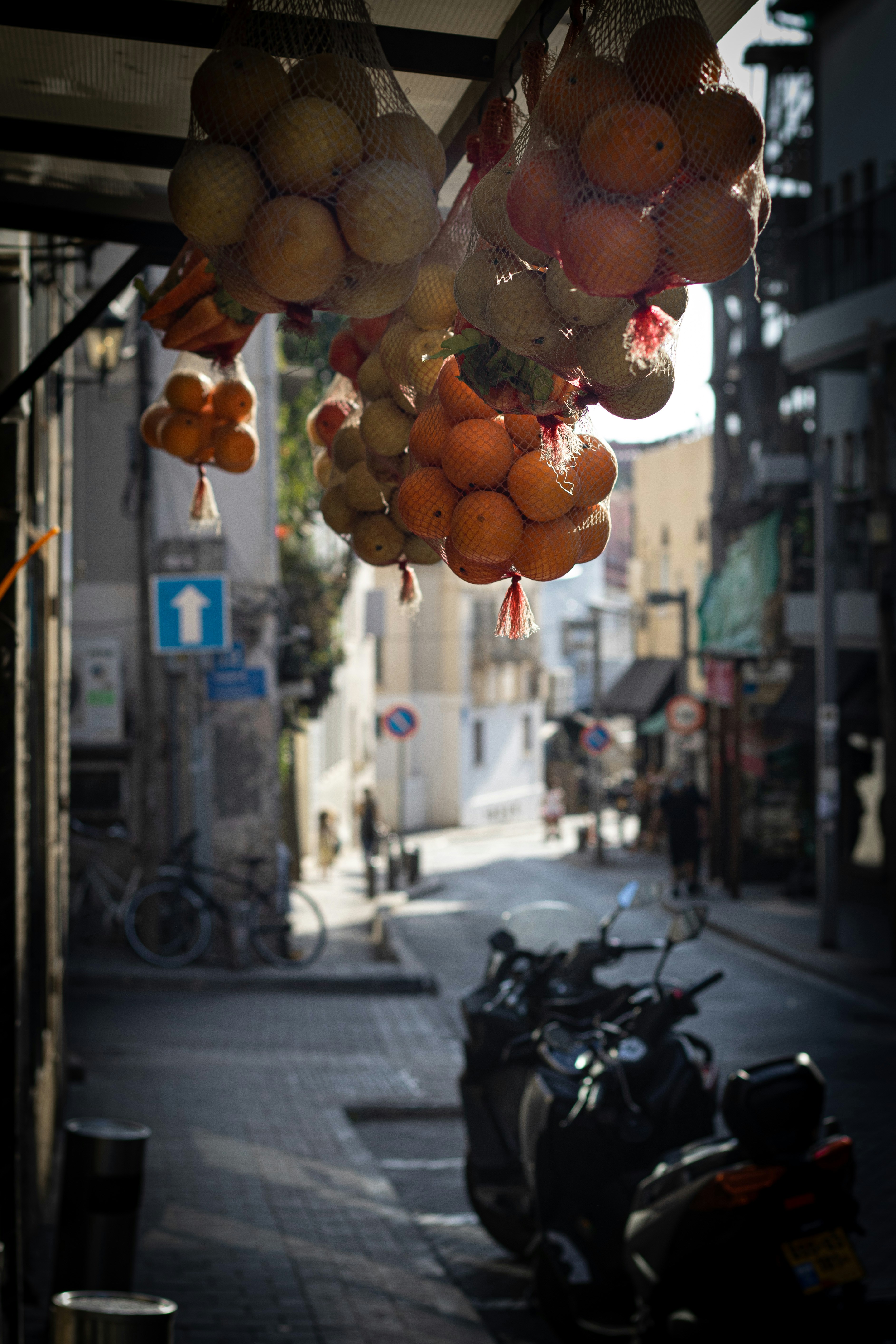 Oranges Under a Sunlit Canopy Over a Quiet Alley