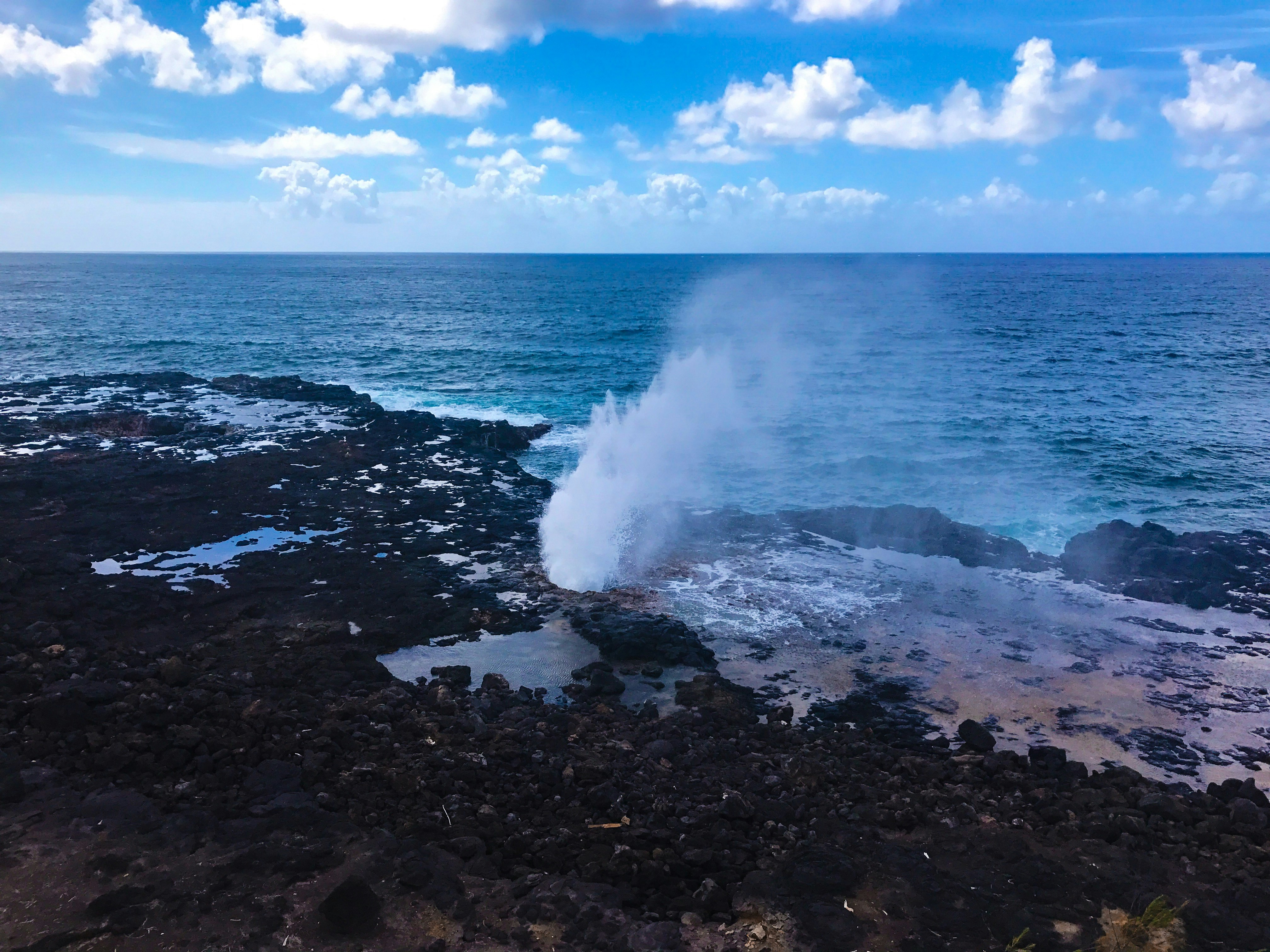 ocean waves crashing on rocks under blue sky during daytime