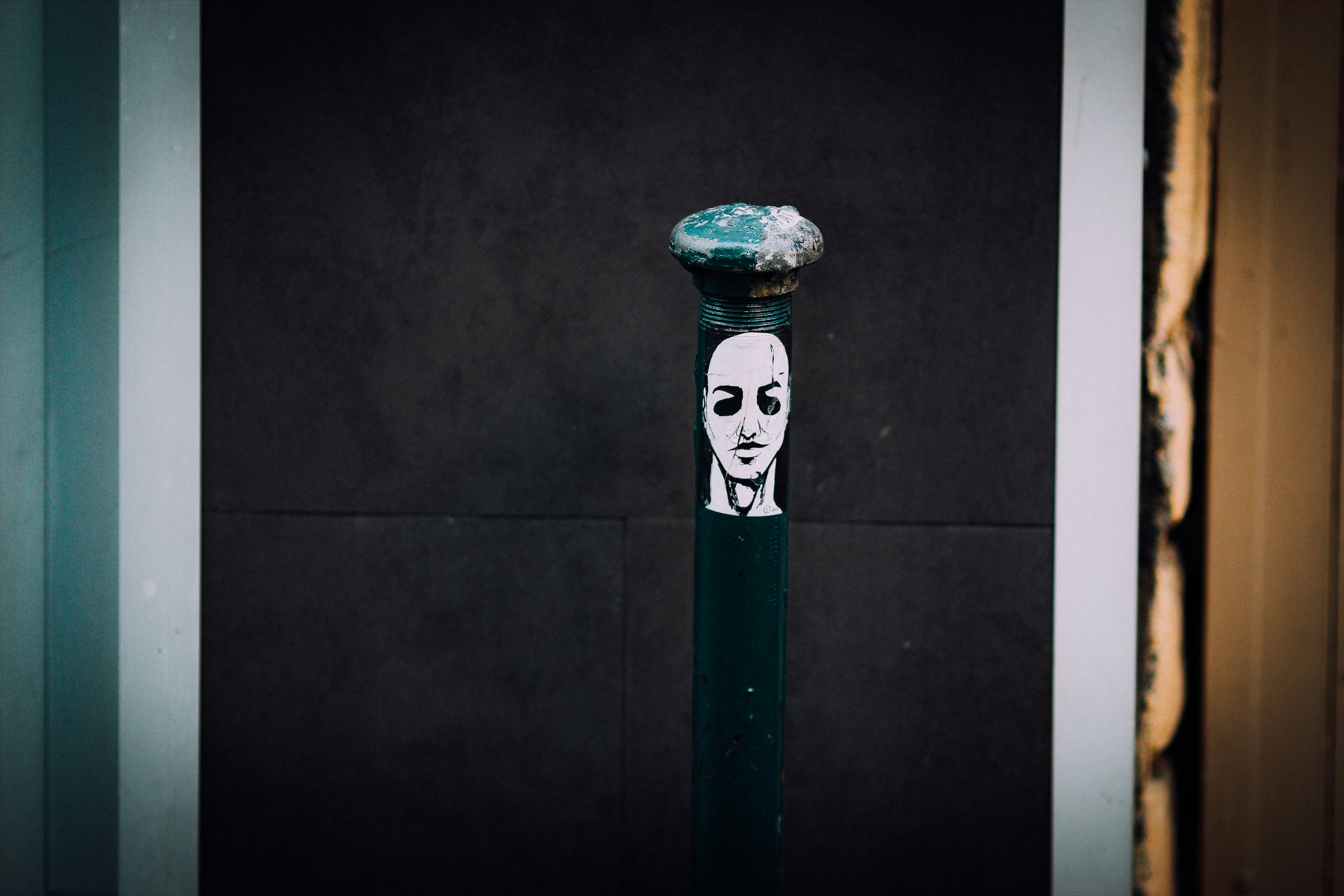 Urban Face on a Pole: A Street Art Obelisk Under Streetlight Shadow