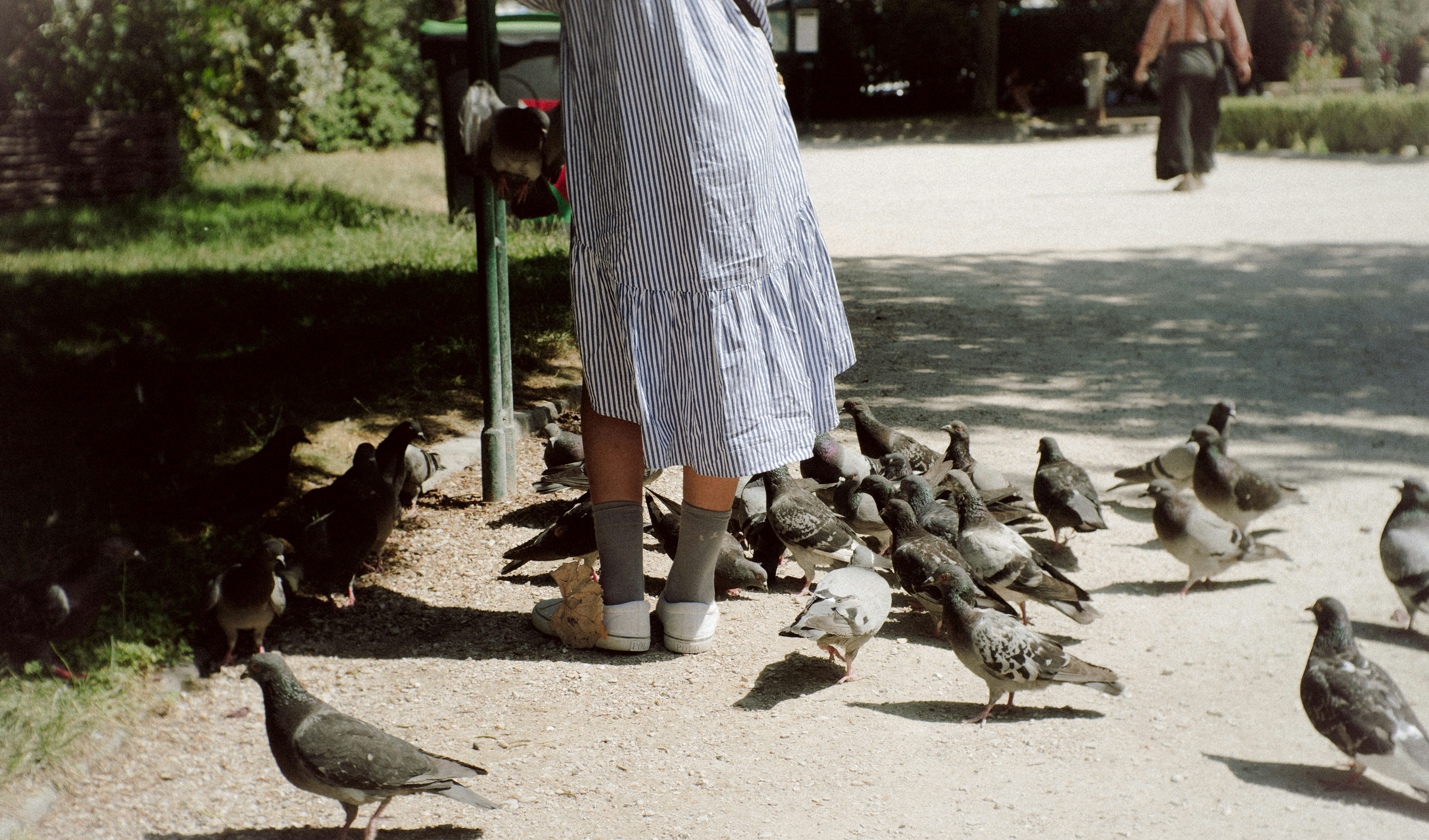 woman in blue and white plaid skirt standing on brown sand during daytime