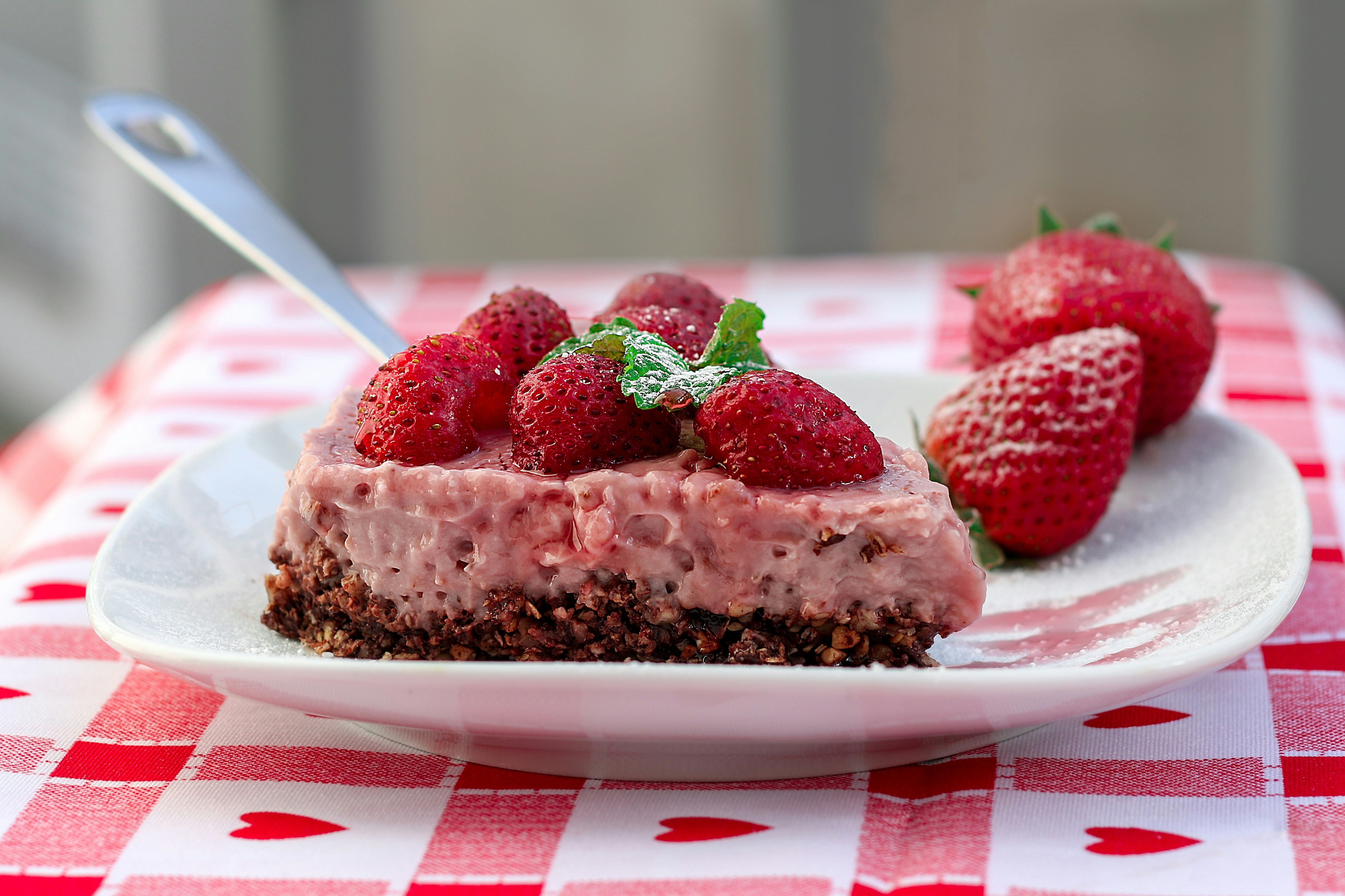 Strawberry-Topped Cheesecake Slice on a Checkerboard Table