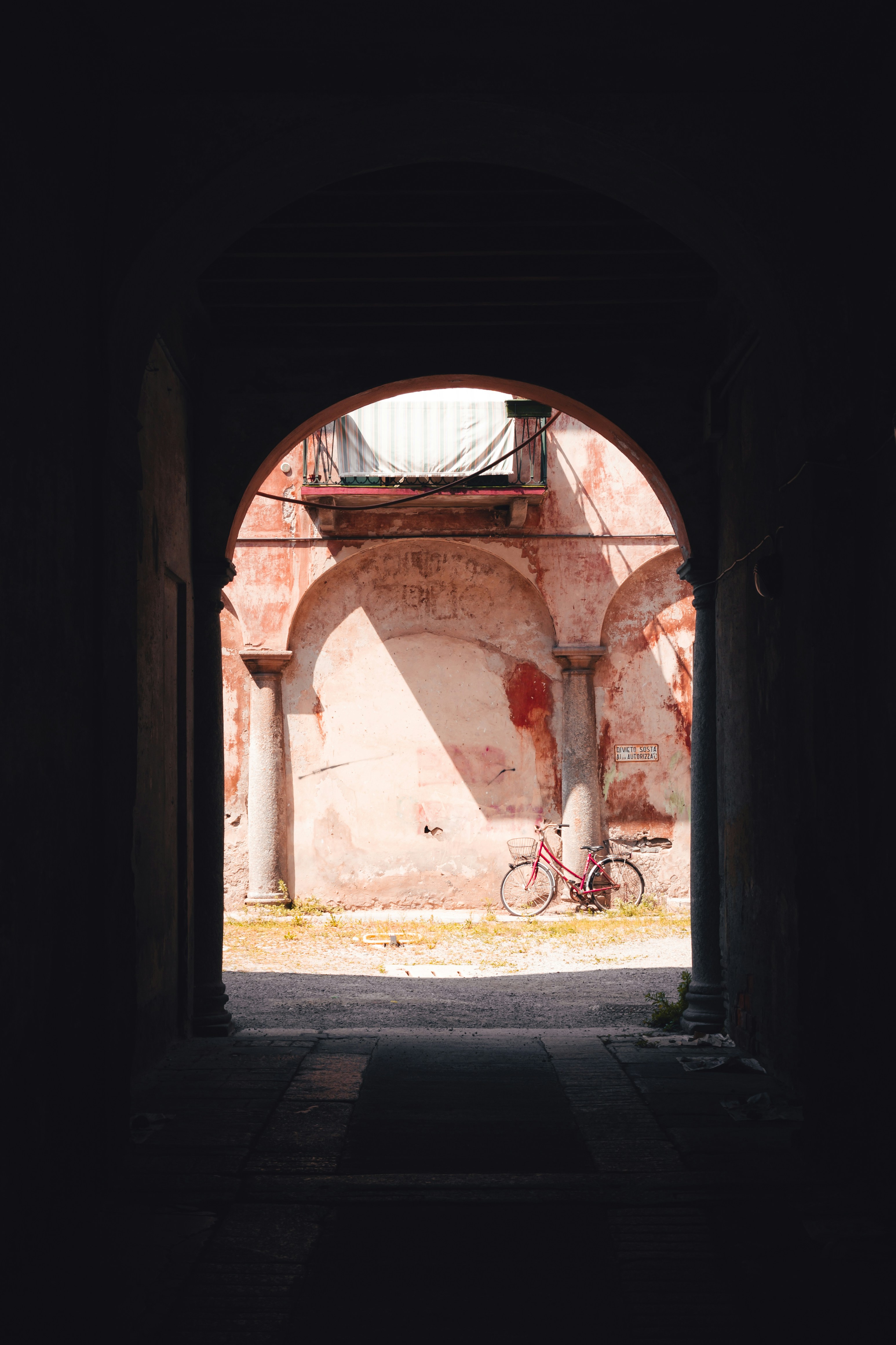 A vintage bicycle rests against a weathered wall in a sunlit archway, evoking a sense of nostalgia and tranquility.