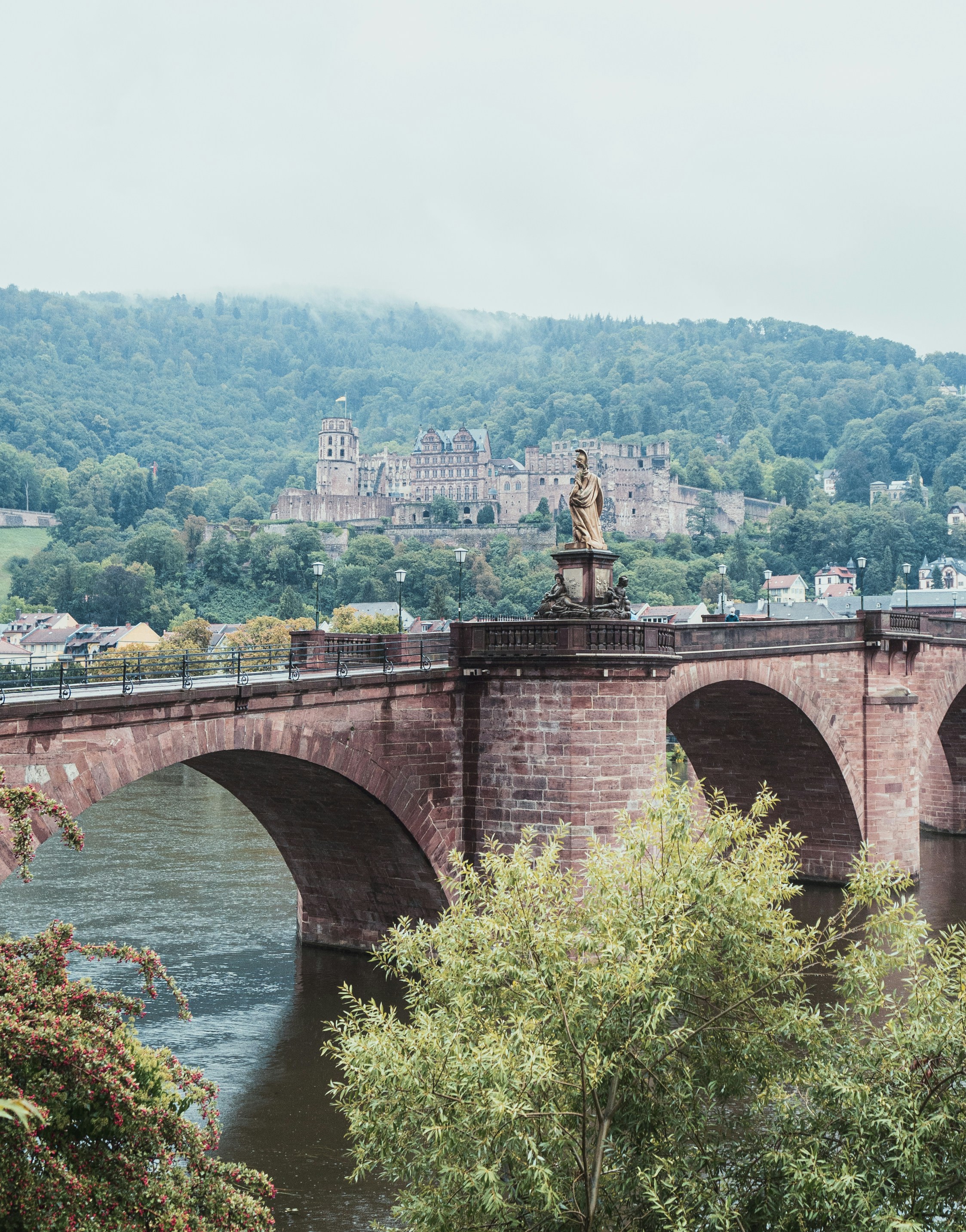 Old Bridge of Heidelberg against the fortress on a cloudy day | brown concrete bridge over river