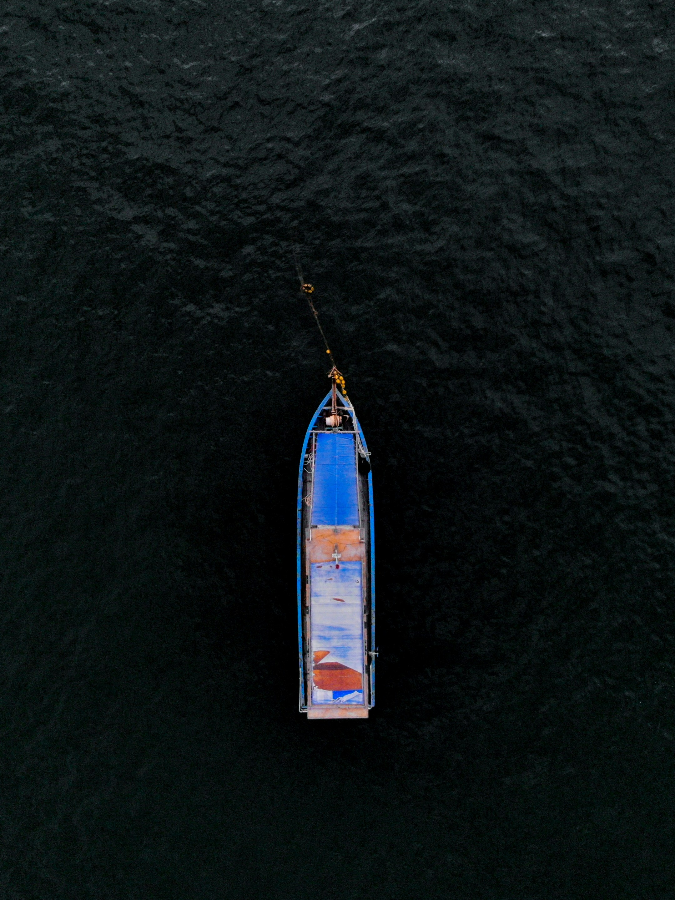Blue-Hulled Vessel Drifts Through Ink-Black Waters