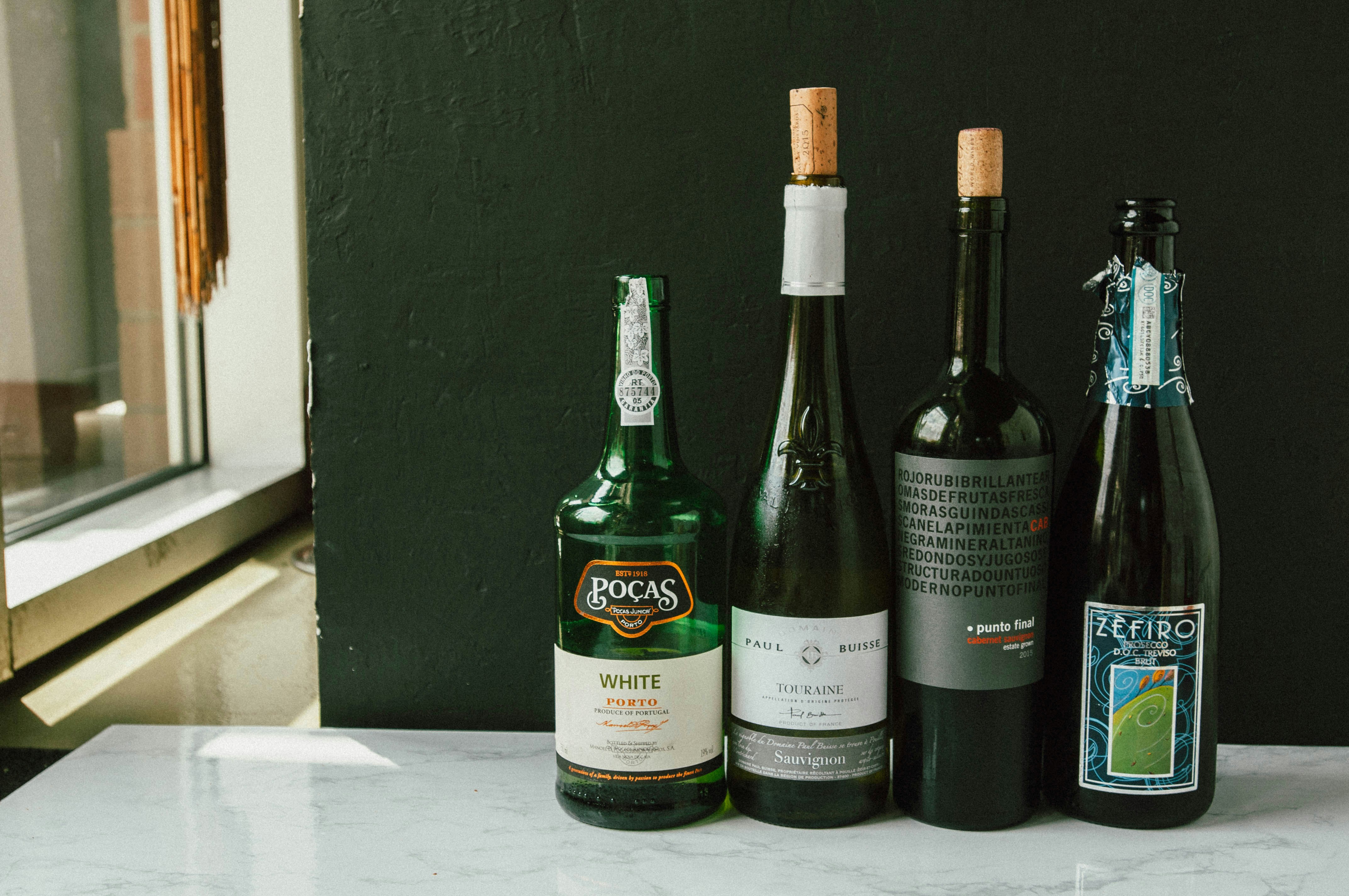 Sunlit Quartet: Four Bottles Stand by a Dark Wall