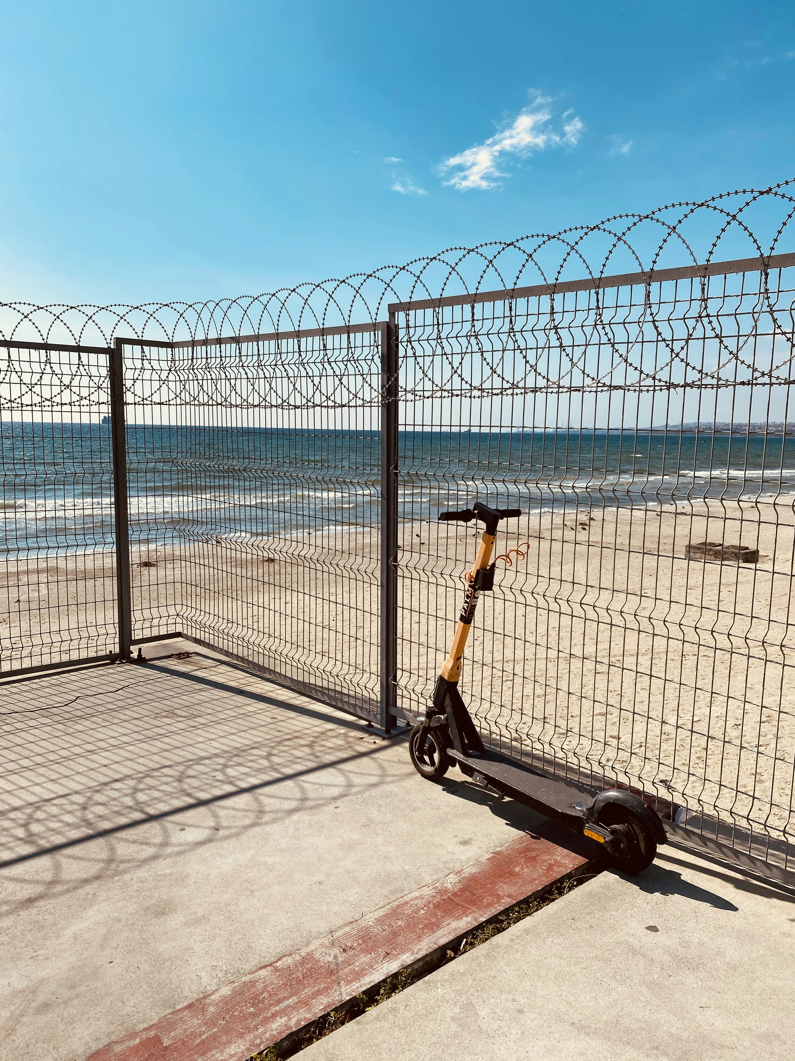 Black and gray kick scooter beside gray steel fence during daytime ...