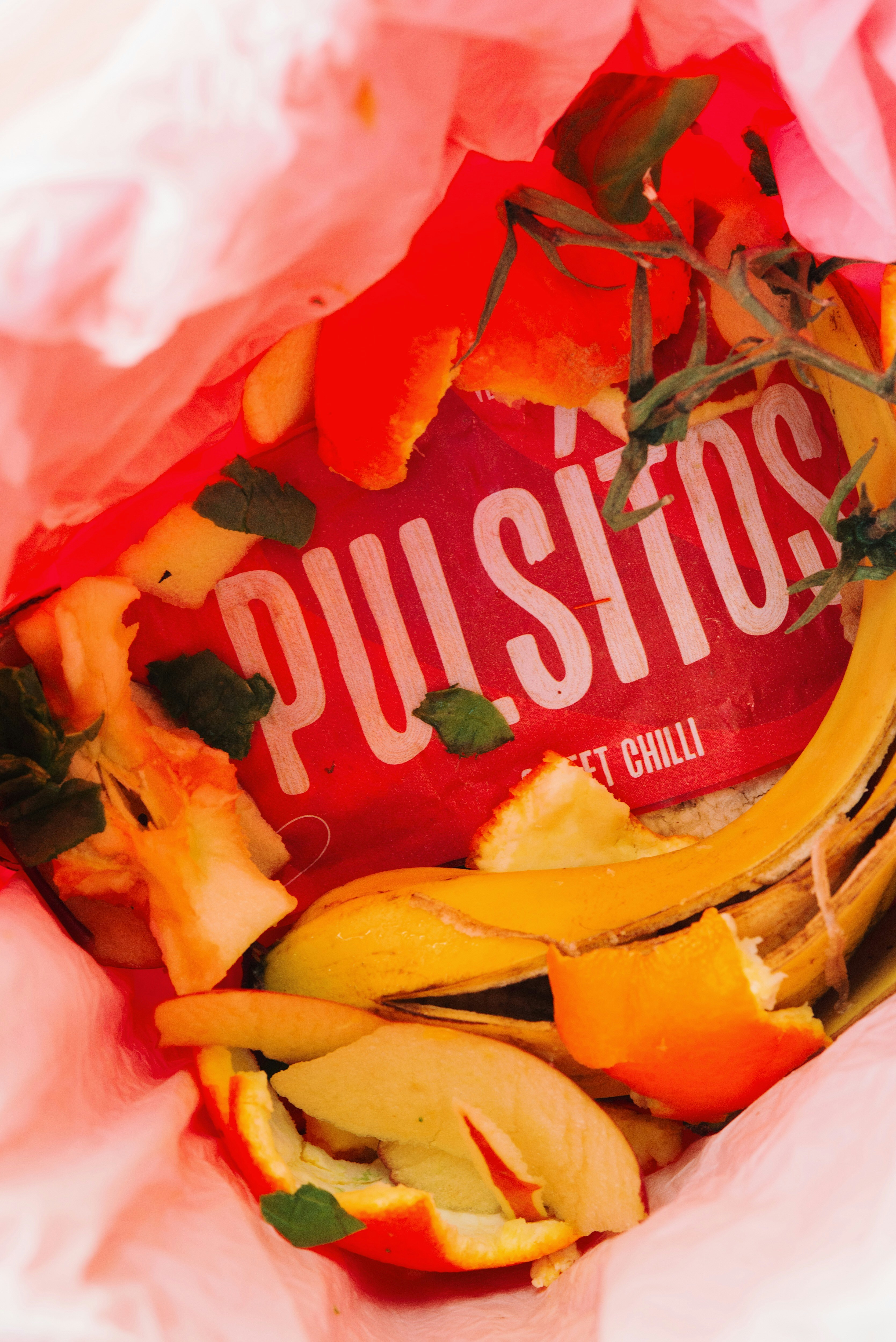 A vibrant collection of fruit peels and scraps, featuring a red label that reads 'PULSITOS' amidst the refuse. The scene captures the remnants of a meal, blending colors and textures.