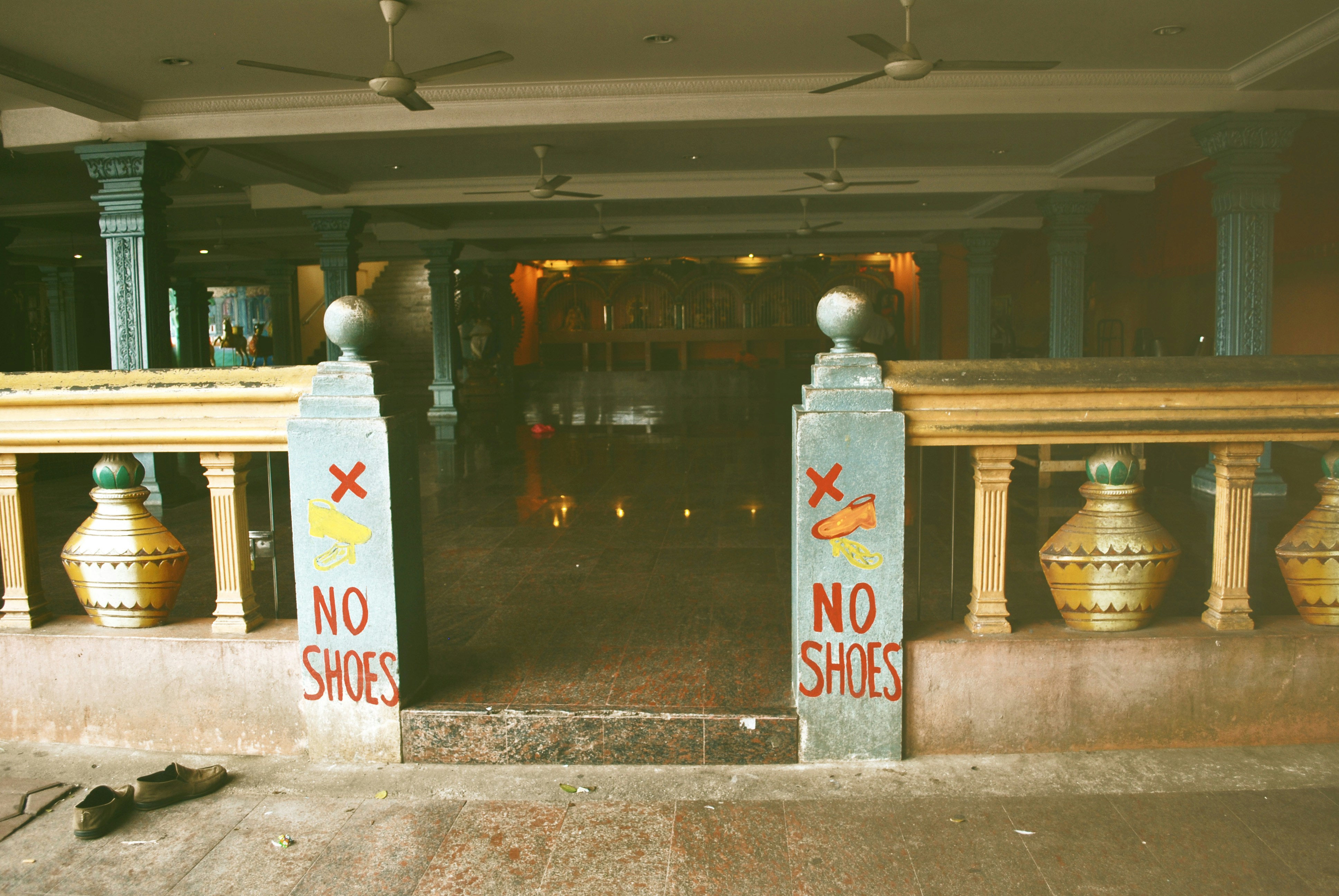Temple Threshold: No Shoes Signposts Framing a Dimly Lit Corridor