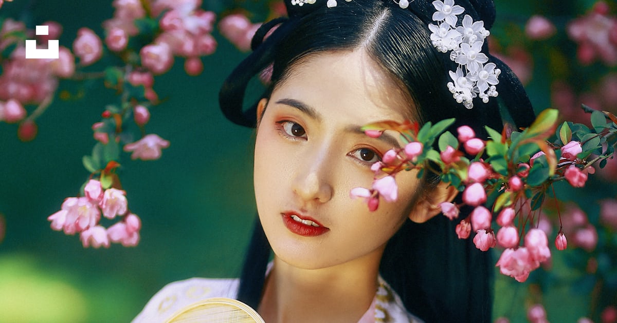 흰색과 분홍색 꽃 드레스를 입은 여자 갈색 나무 둥근 모자를 들고 사진 Unsplash의 무료 꽃 이미지