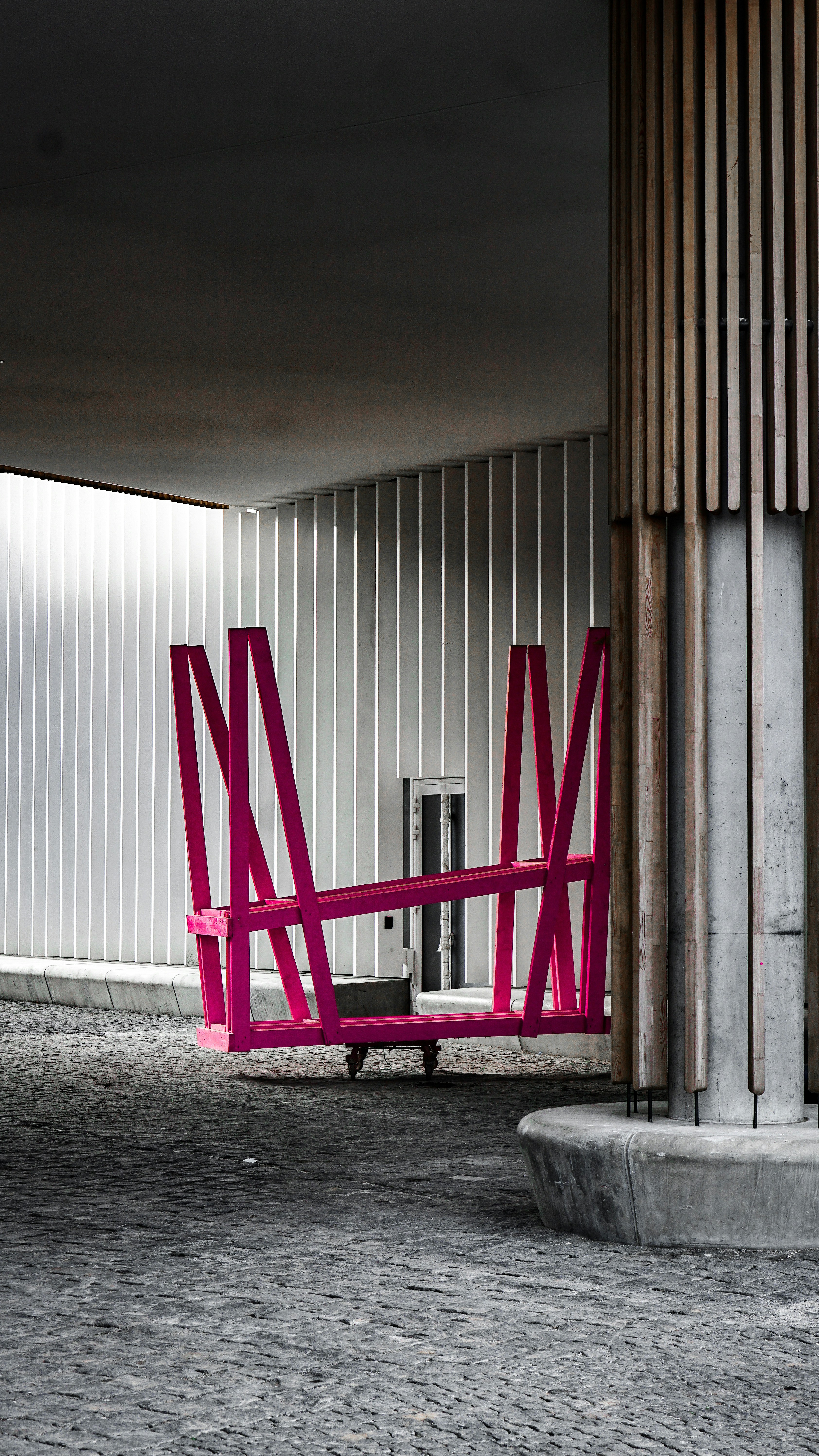 Vibrant pink architectural element juxtaposed against muted concrete and wood textures in a contemporary space.