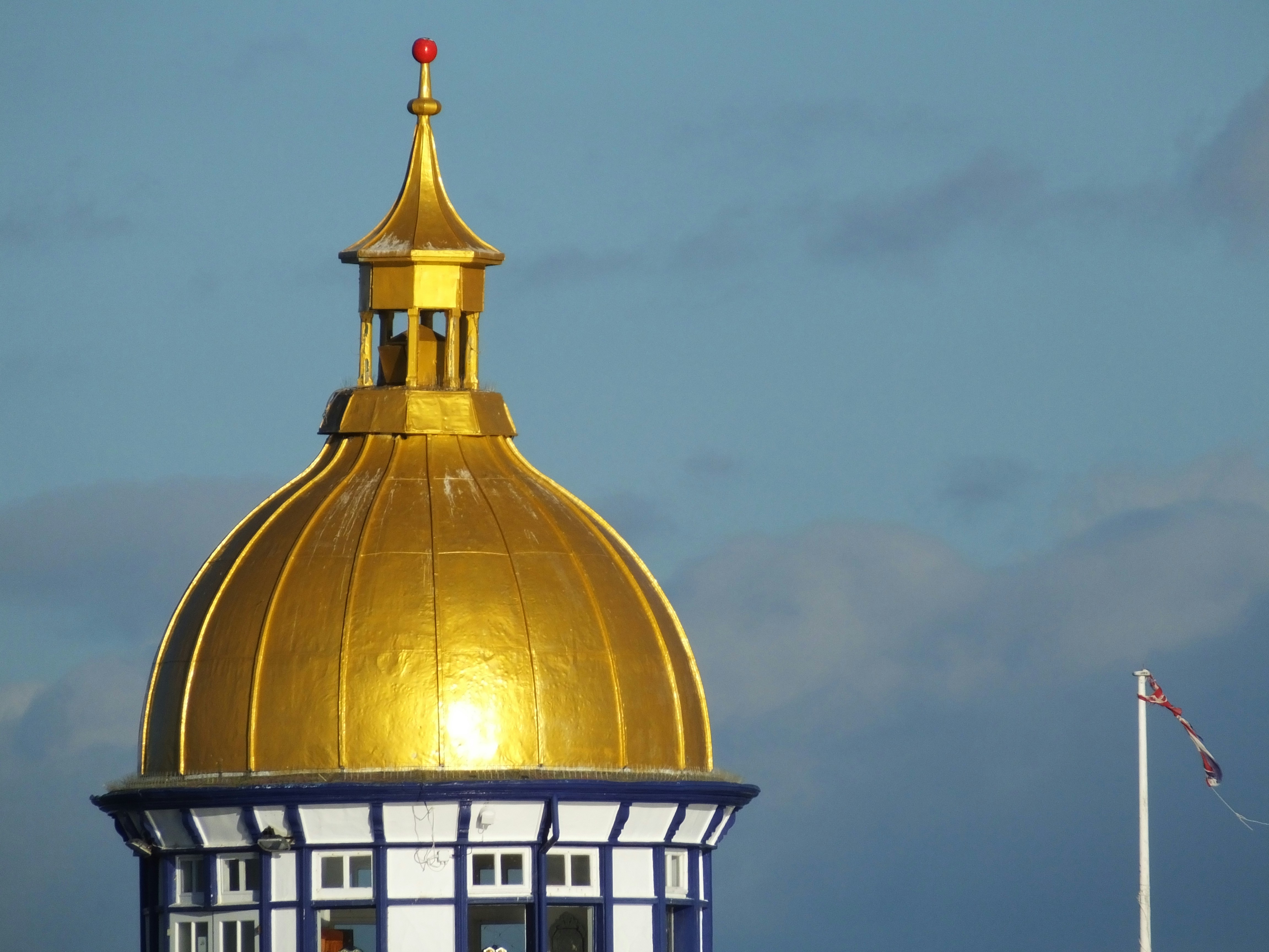 Golden domed structure with blue and white accents under a clear sky.