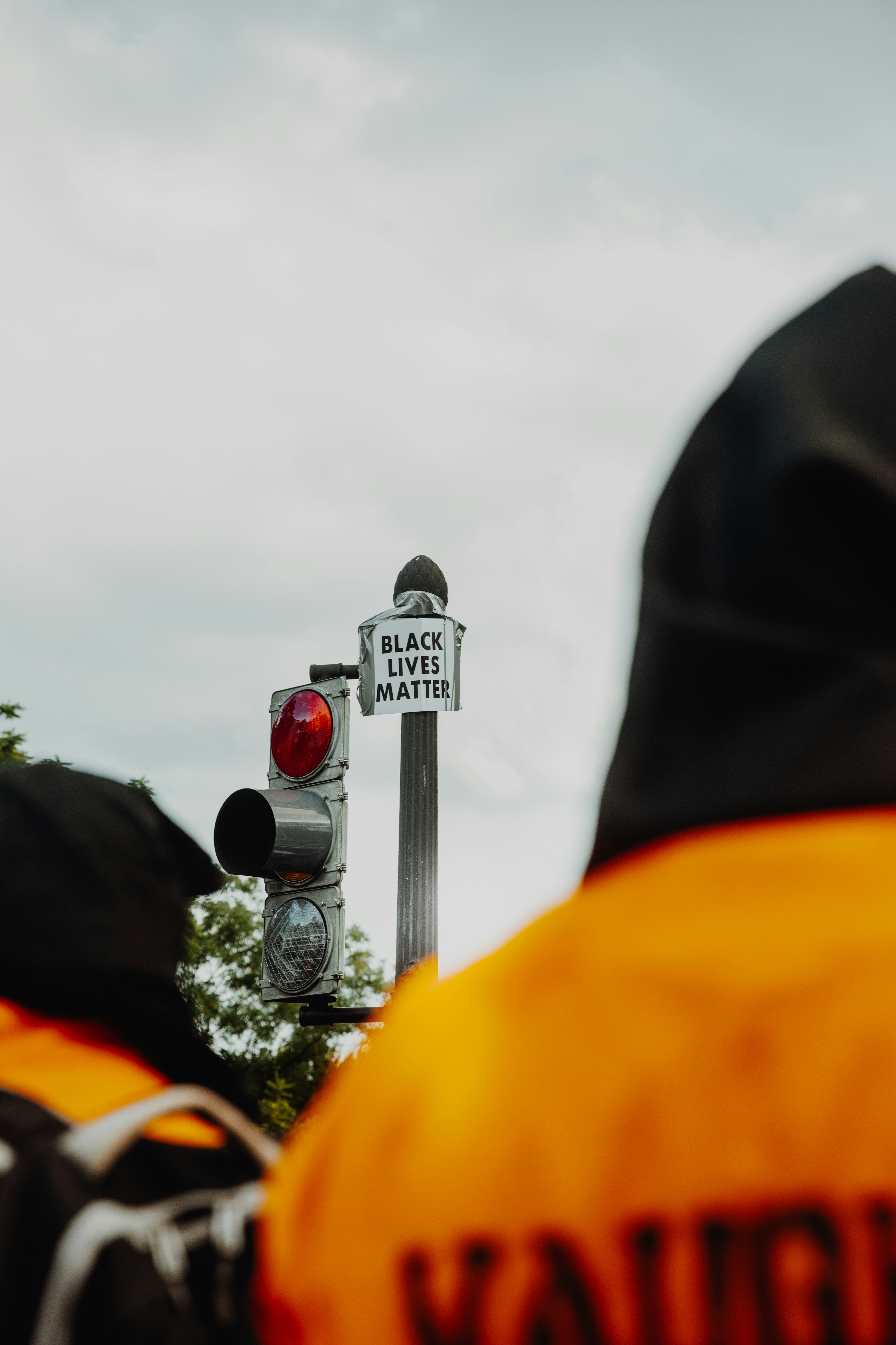 Crosswalk Moment: Black Lives Matter Sign Framed by Orange-Clad Crowd