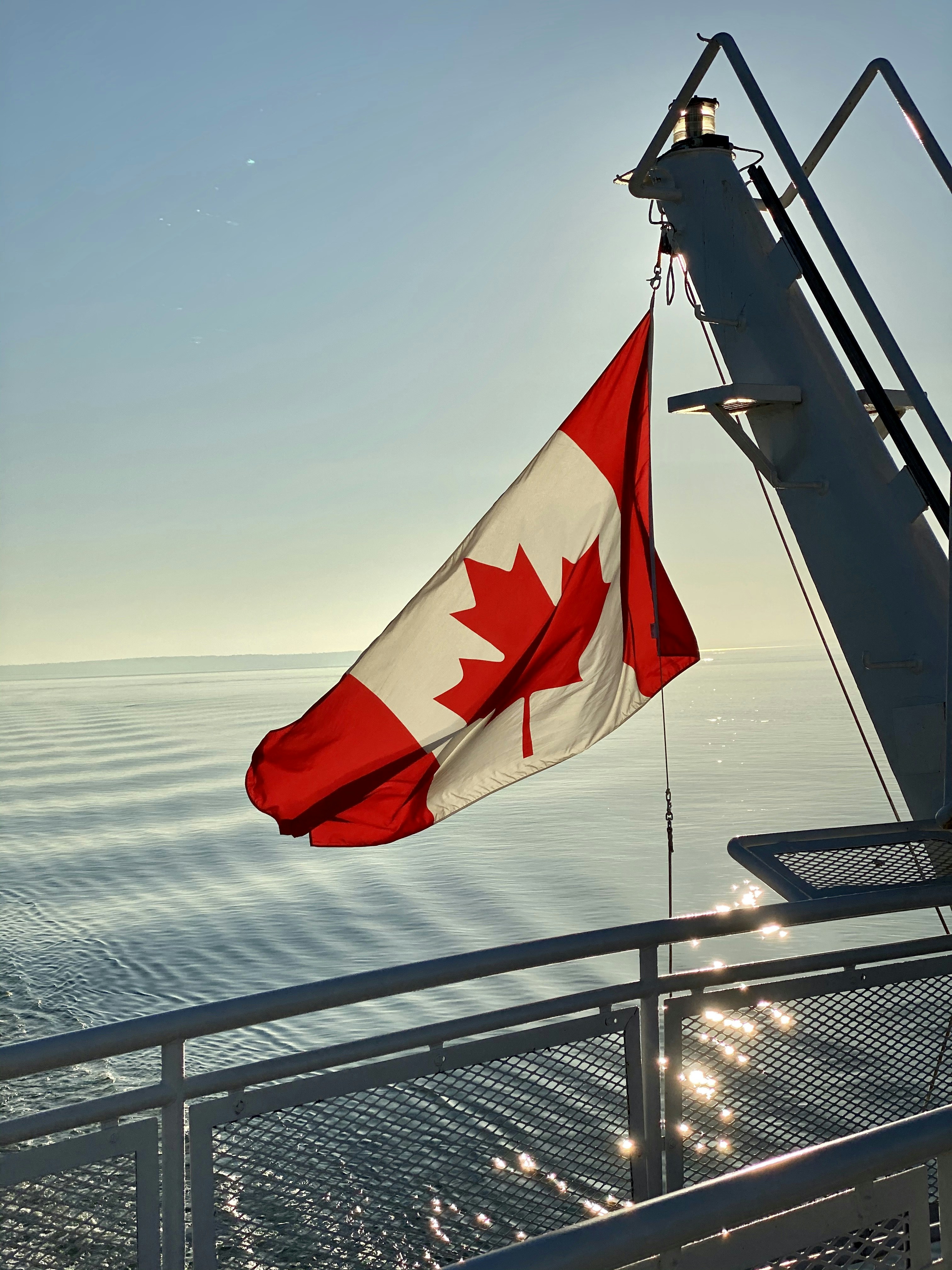 red white and blue flag on gray metal railings near sea during daytime