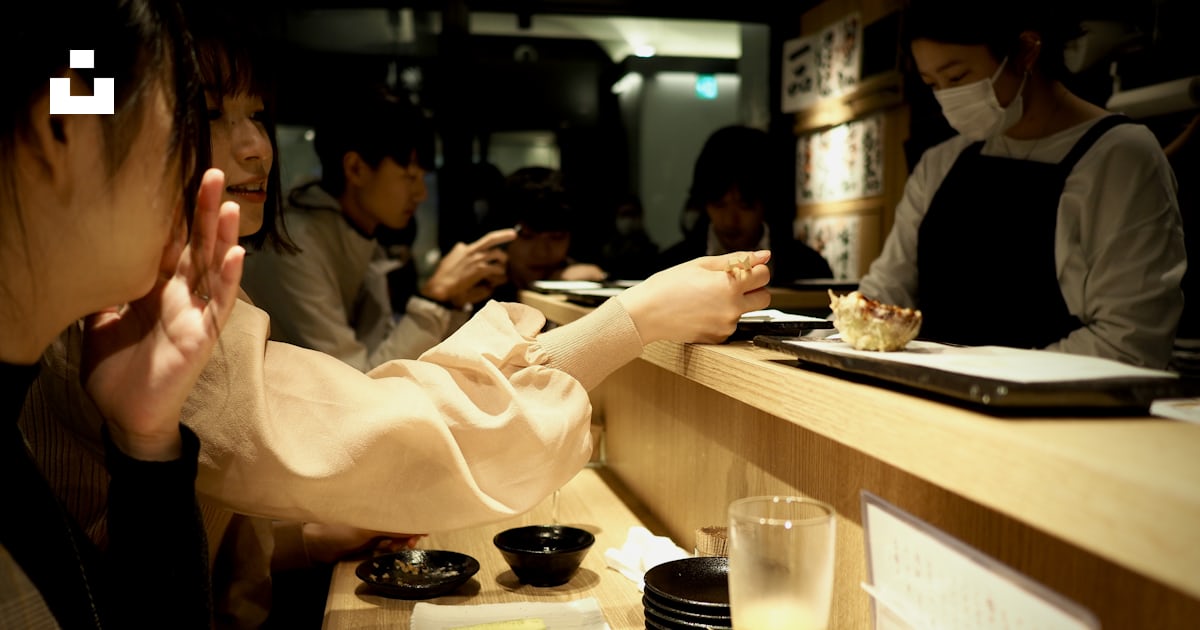 흰색 긴 소매 셔츠를 입은 여자가 음식과 함께 테이블 옆에 앉아 있다 사진 Unsplash의 무료 도쿄 이미지