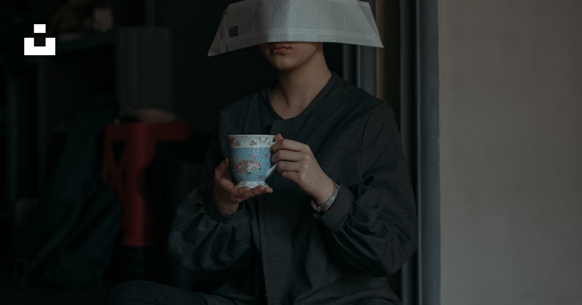 검은 재킷과 검은 바지를 입은 남자가 흰색 세라믹 머그잔을 들고 바닥에 앉아 있다 사진 Unsplash의 무료 회색 이미지