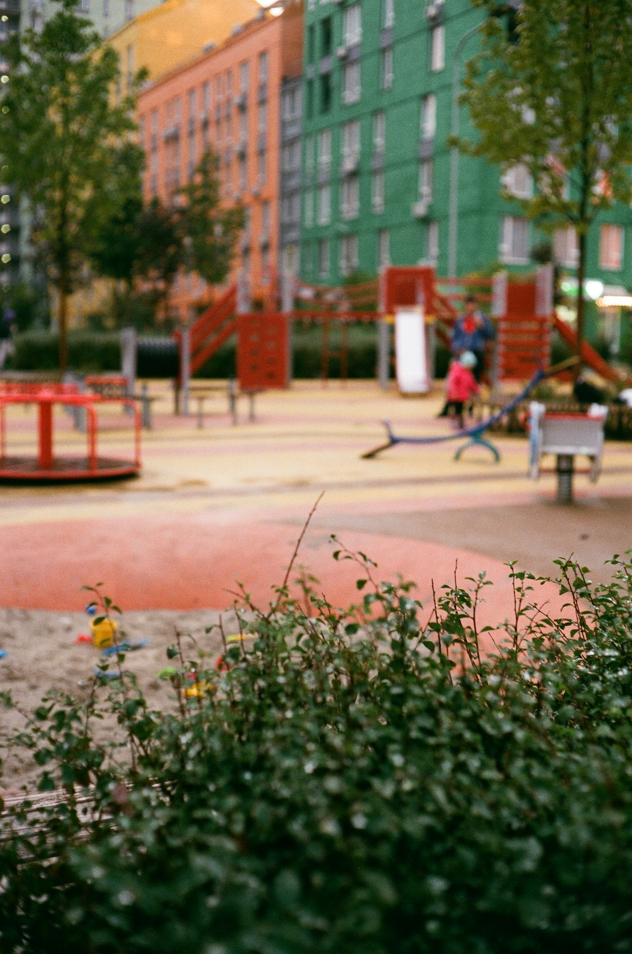 Children enjoying a vibrant playground filled with colorful equipment and greenery. The scene captures the essence of playful outdoor activities.