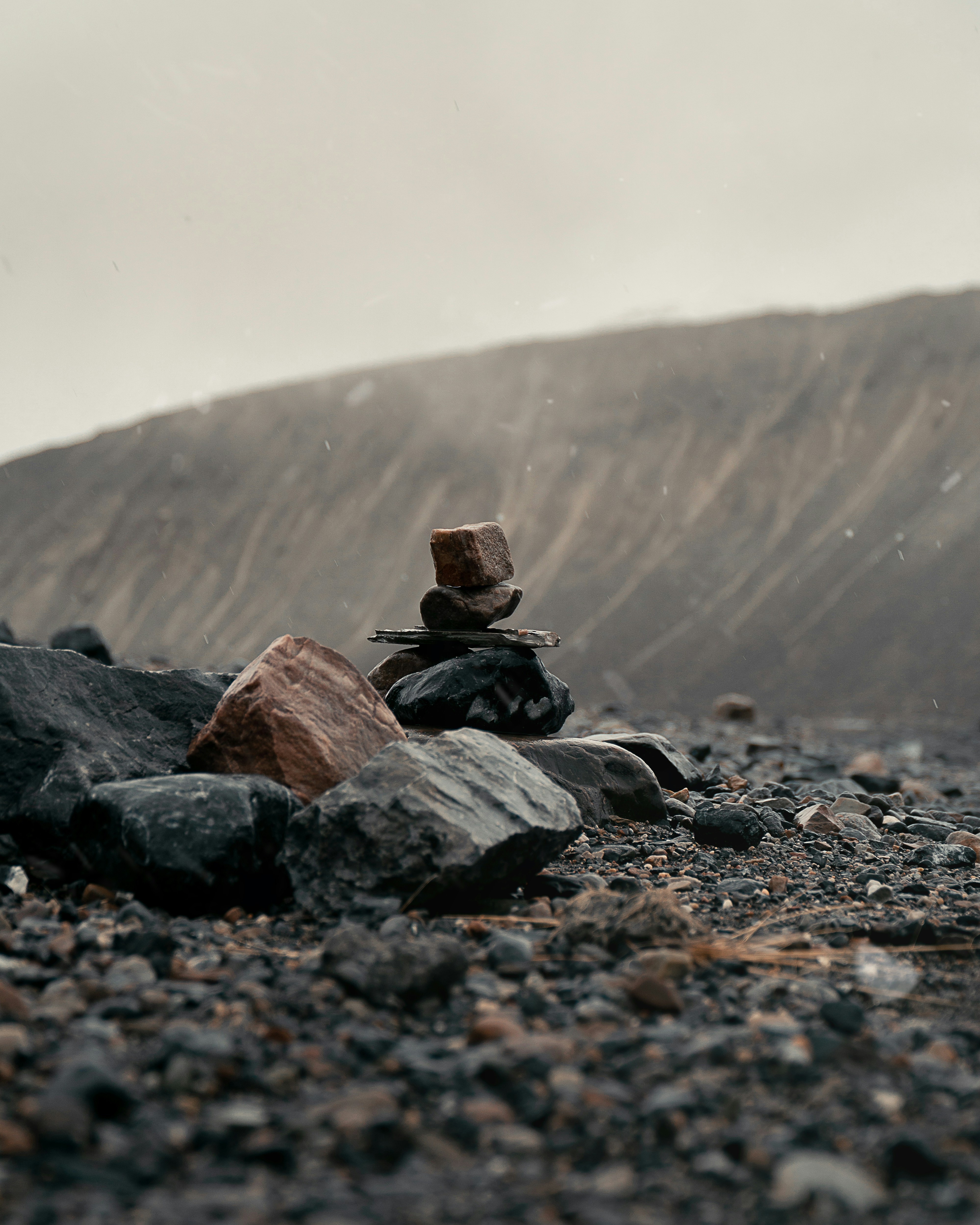Balanced cairn on a windswept shore under a pale sky