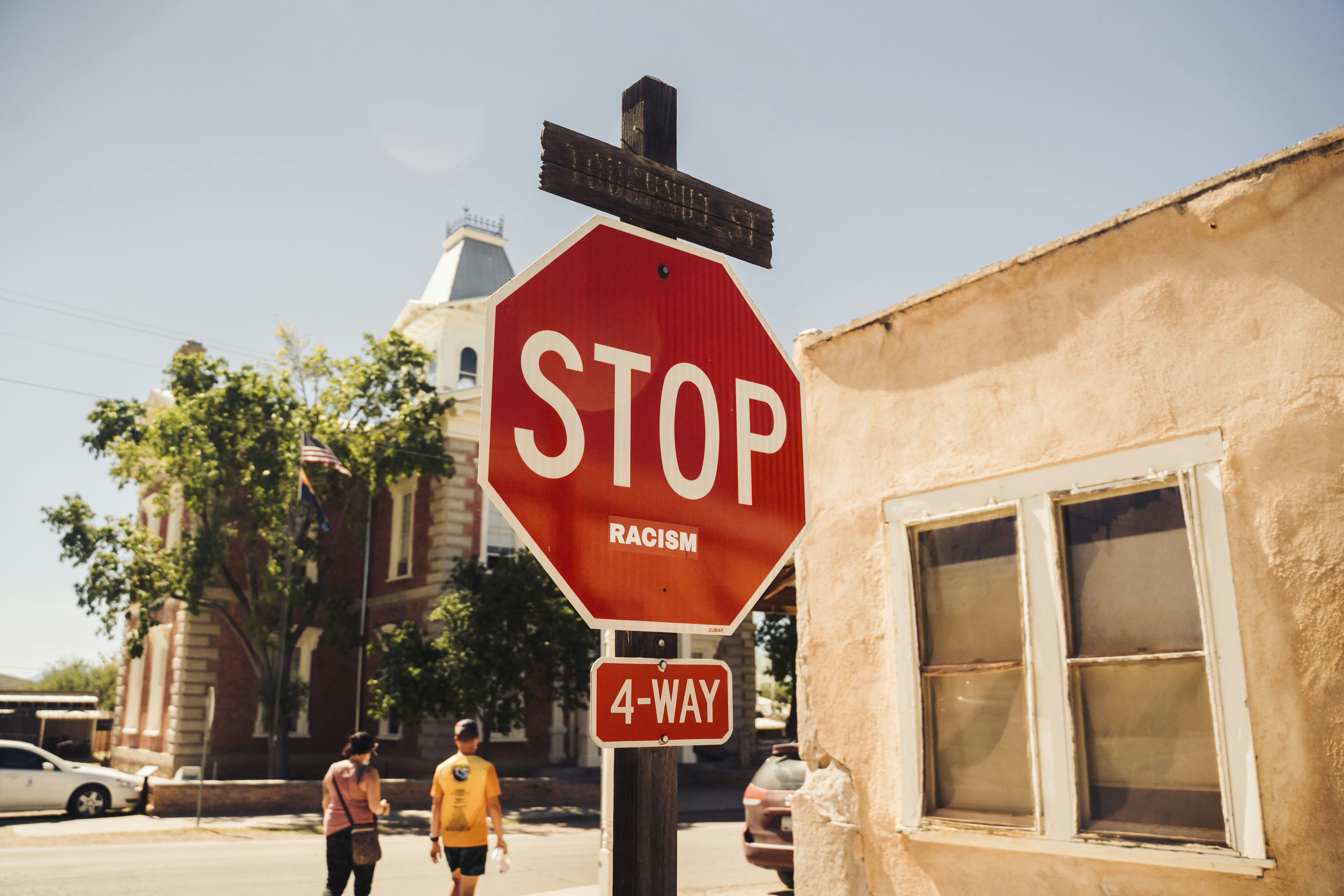 Red stop sign near pedestrians on a sunny sidewalk.
