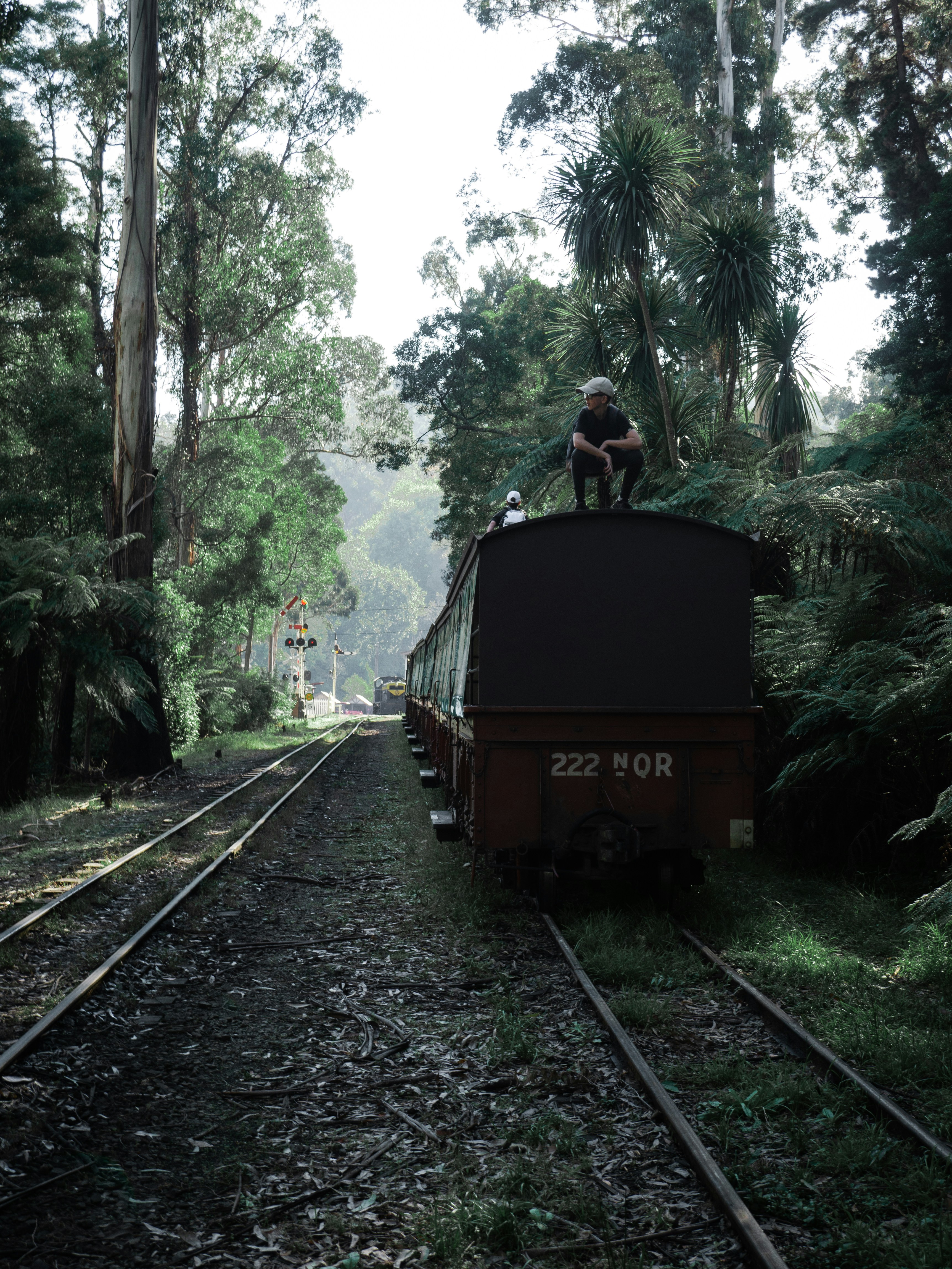 man in red jacket standing on train rail during daytime