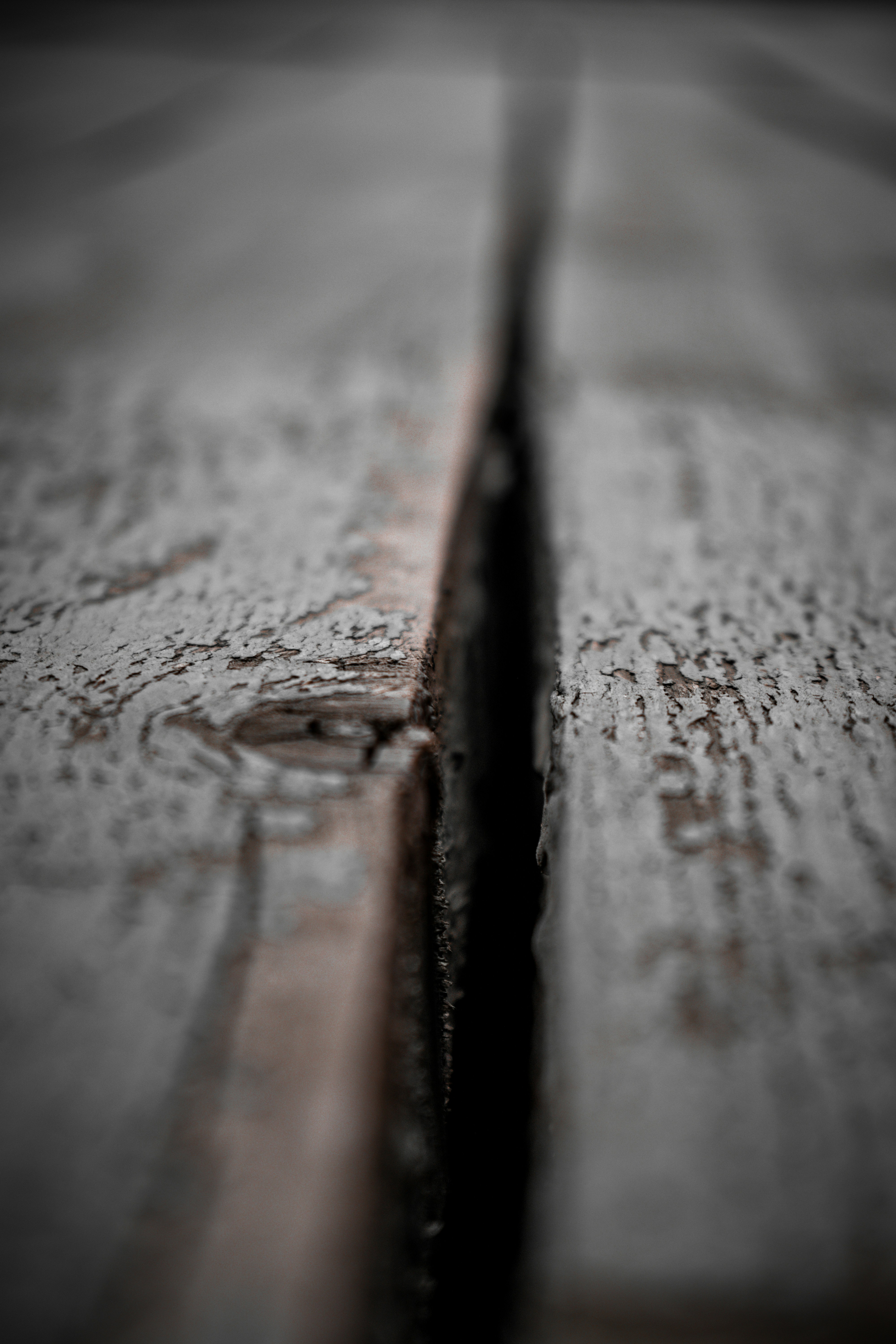 Close-up view of a weathered wooden surface, highlighting a deep crack that reveals the texture and history of the wood.
