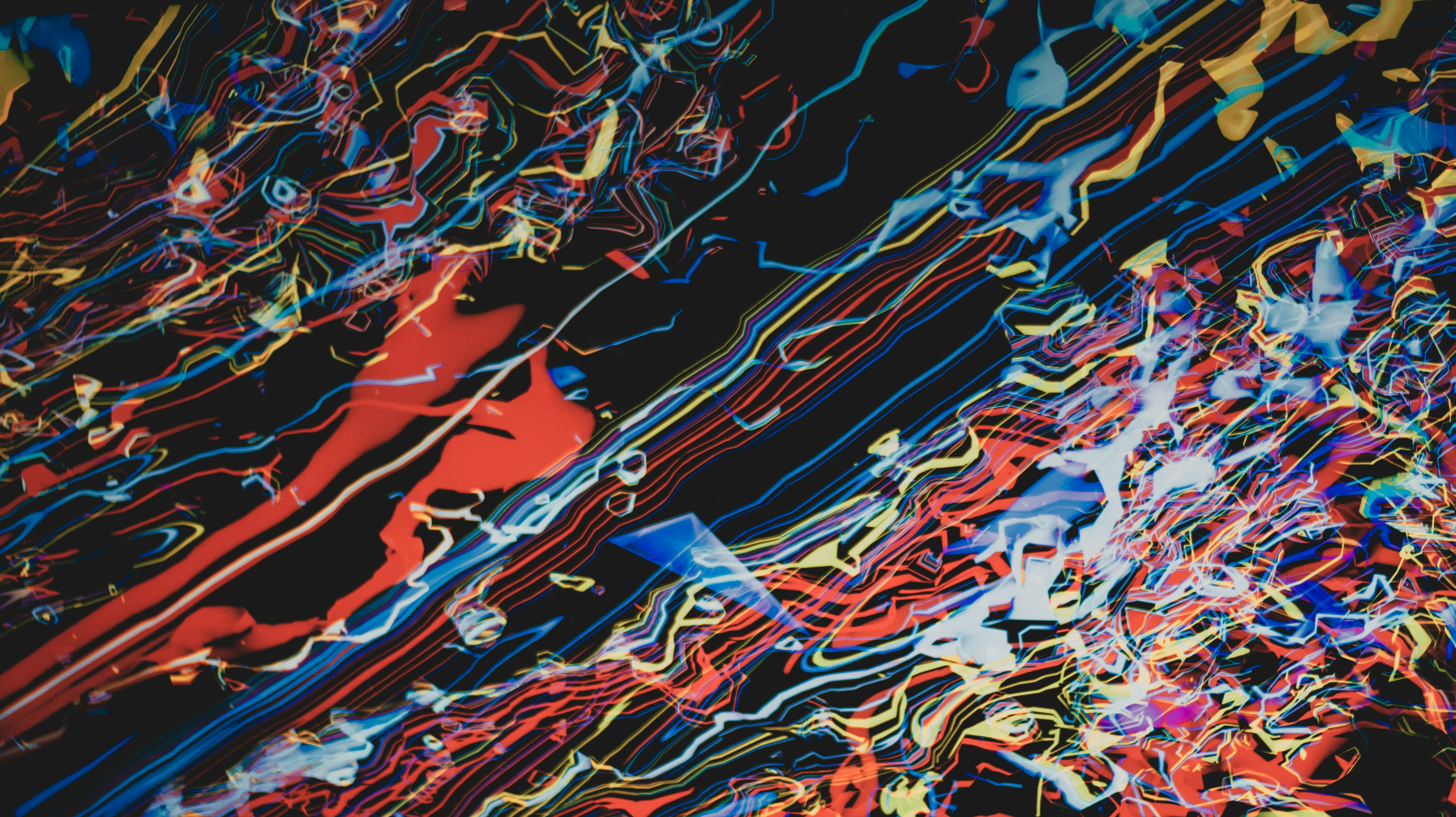 Abstract composition featuring vibrant, swirling lines and shapes in red, blue, and yellow against a dark background.