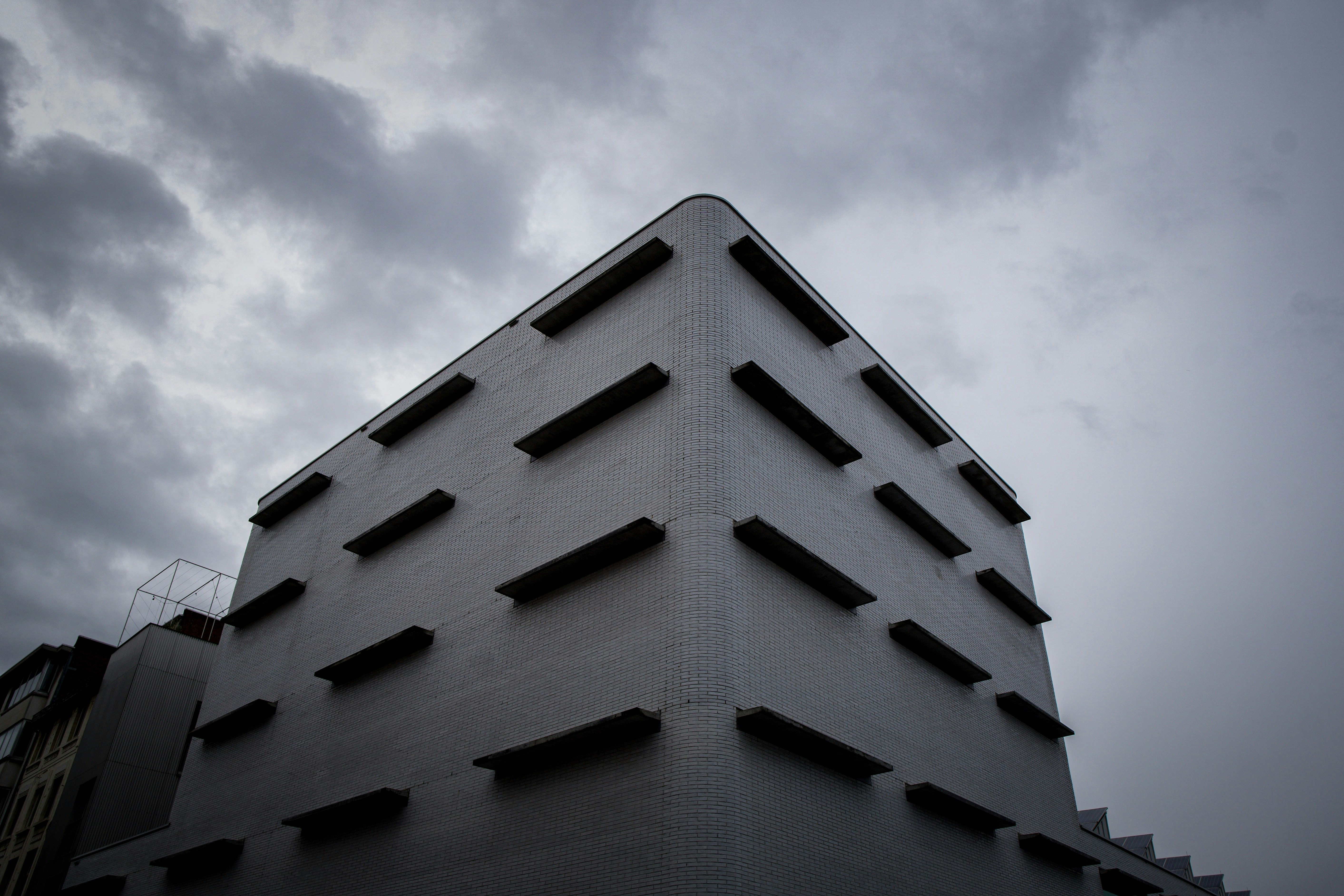Abstract architectural detail showcasing a minimalist white building with protruding ledges against a moody sky.