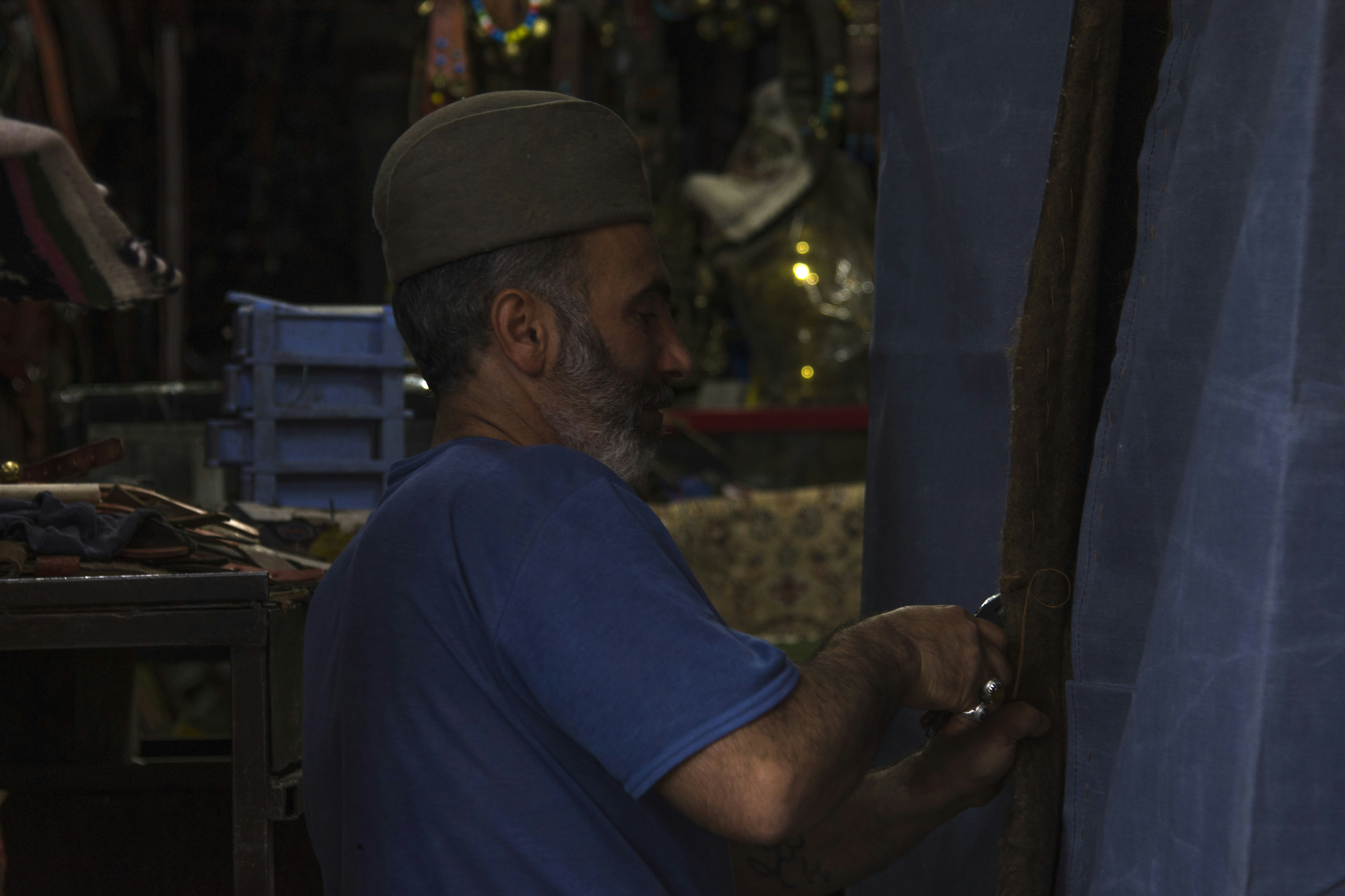 man in blue crew neck t-shirt and brown cap holding brown wooden stick