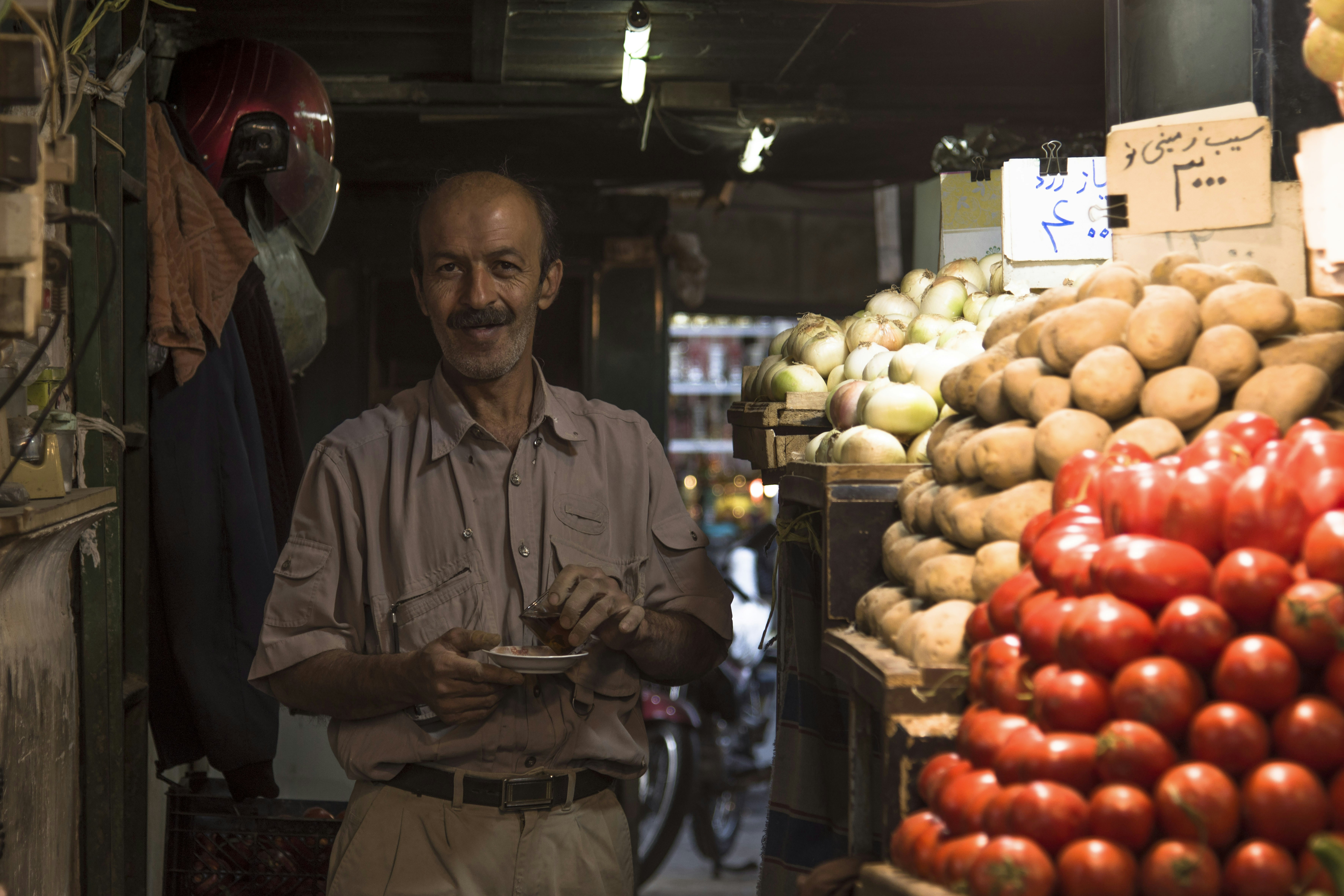 Evening Market Vendor: Plate in Hand Amid Colorful Produce