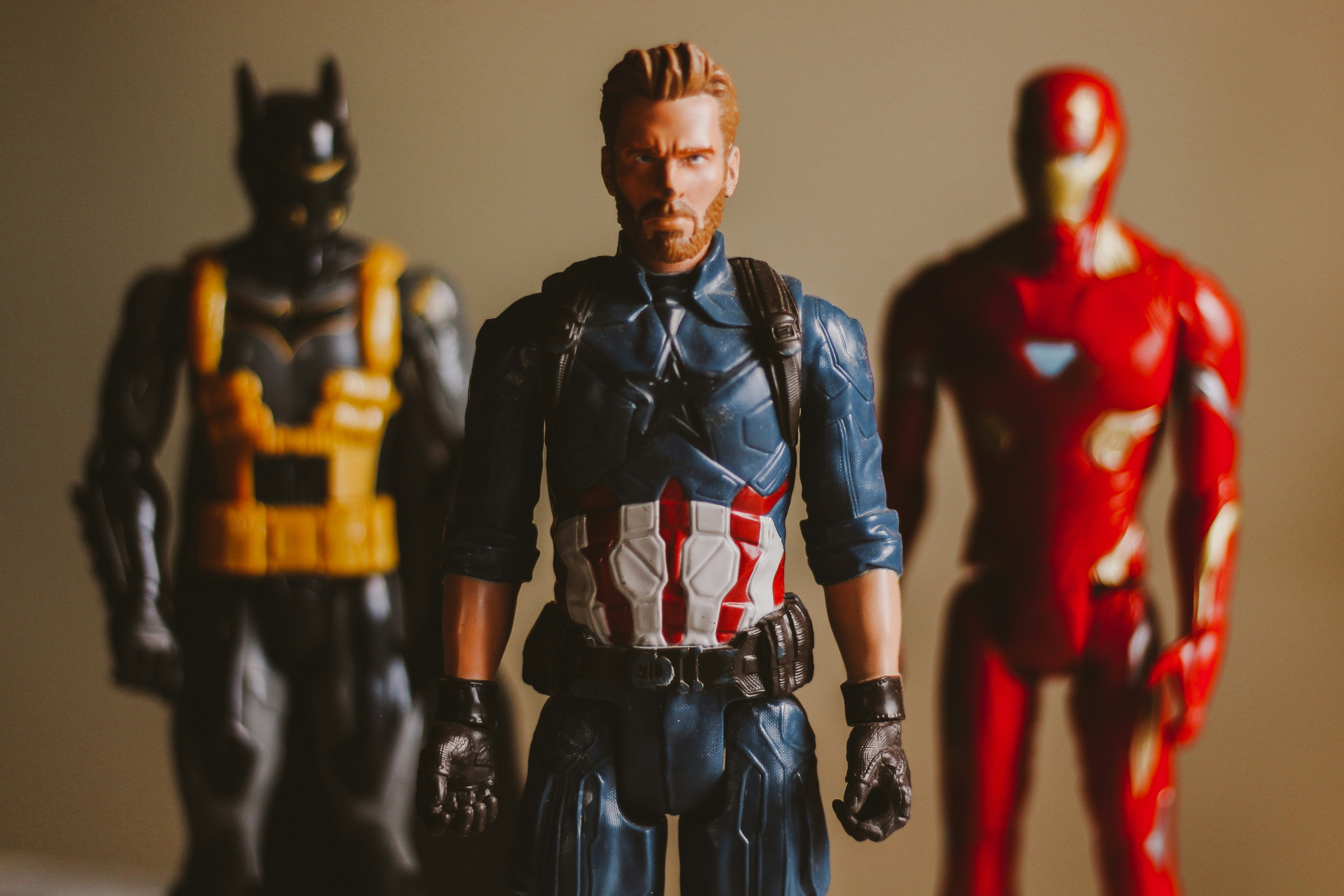 Action figures of three superheroes standing in a lineup with a soft-focus background.
