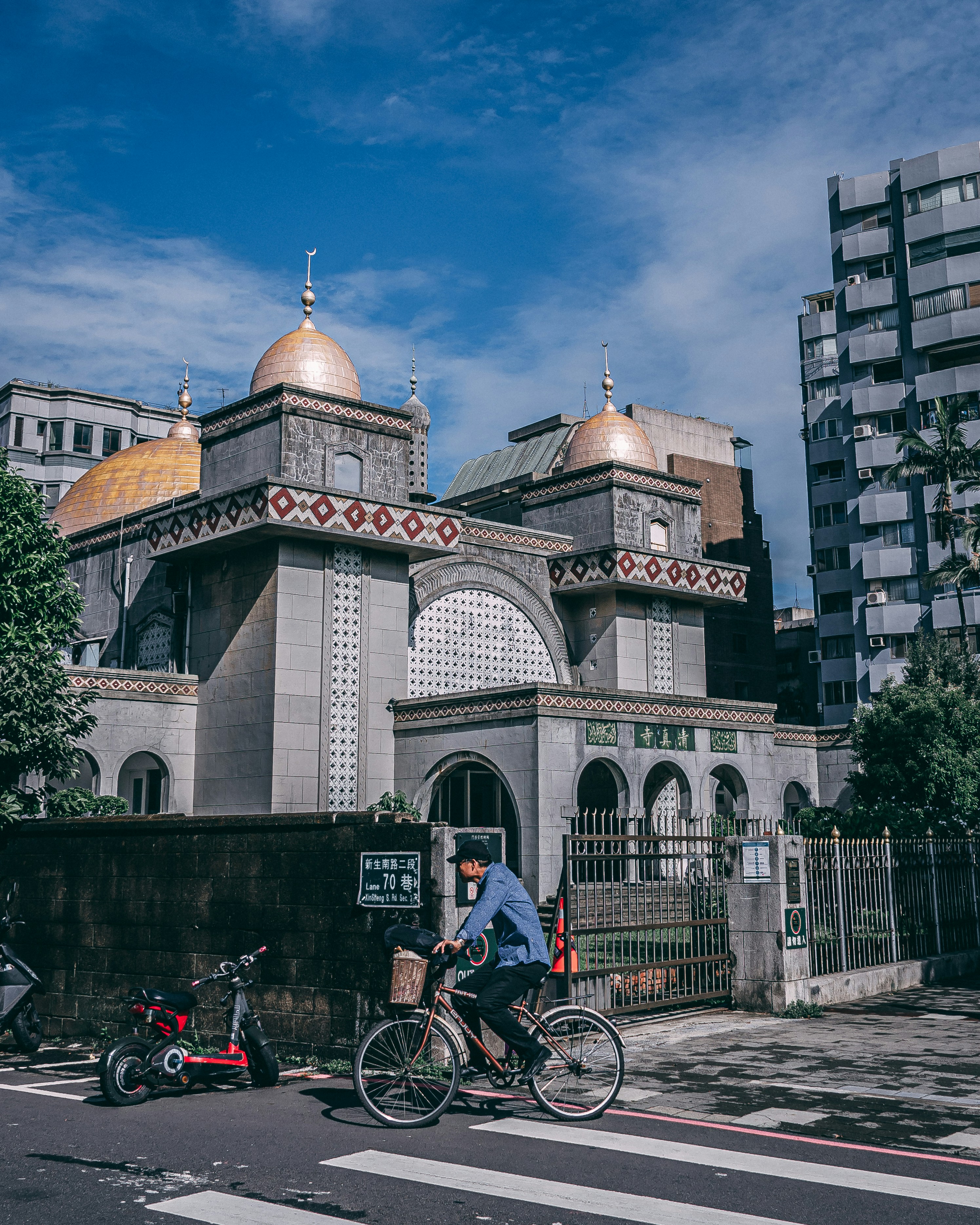 people riding bicycle near white and brown concrete building during daytime
