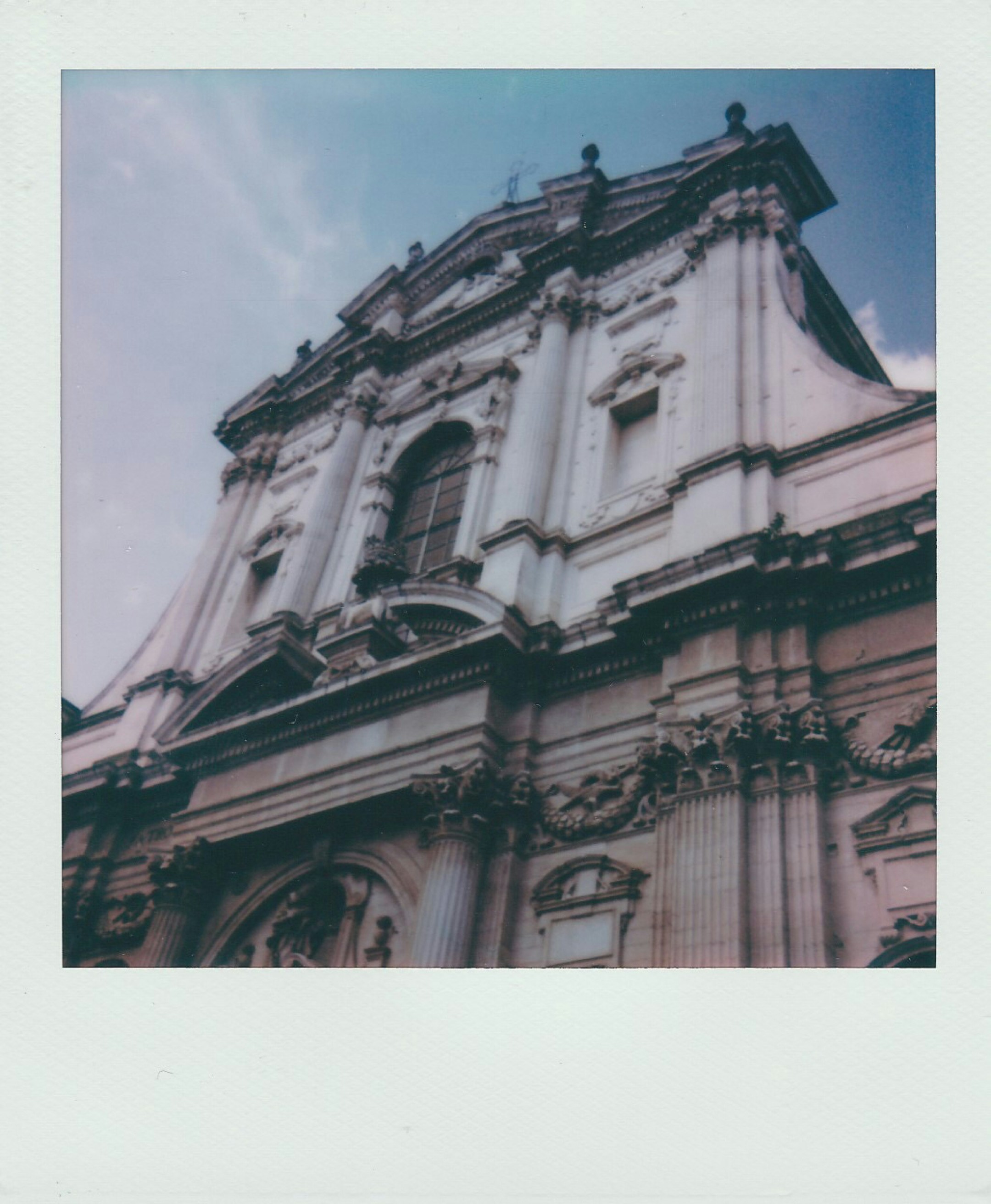 Ornate building facade captured from a low angle, showcasing intricate details and a dramatic sky backdrop.