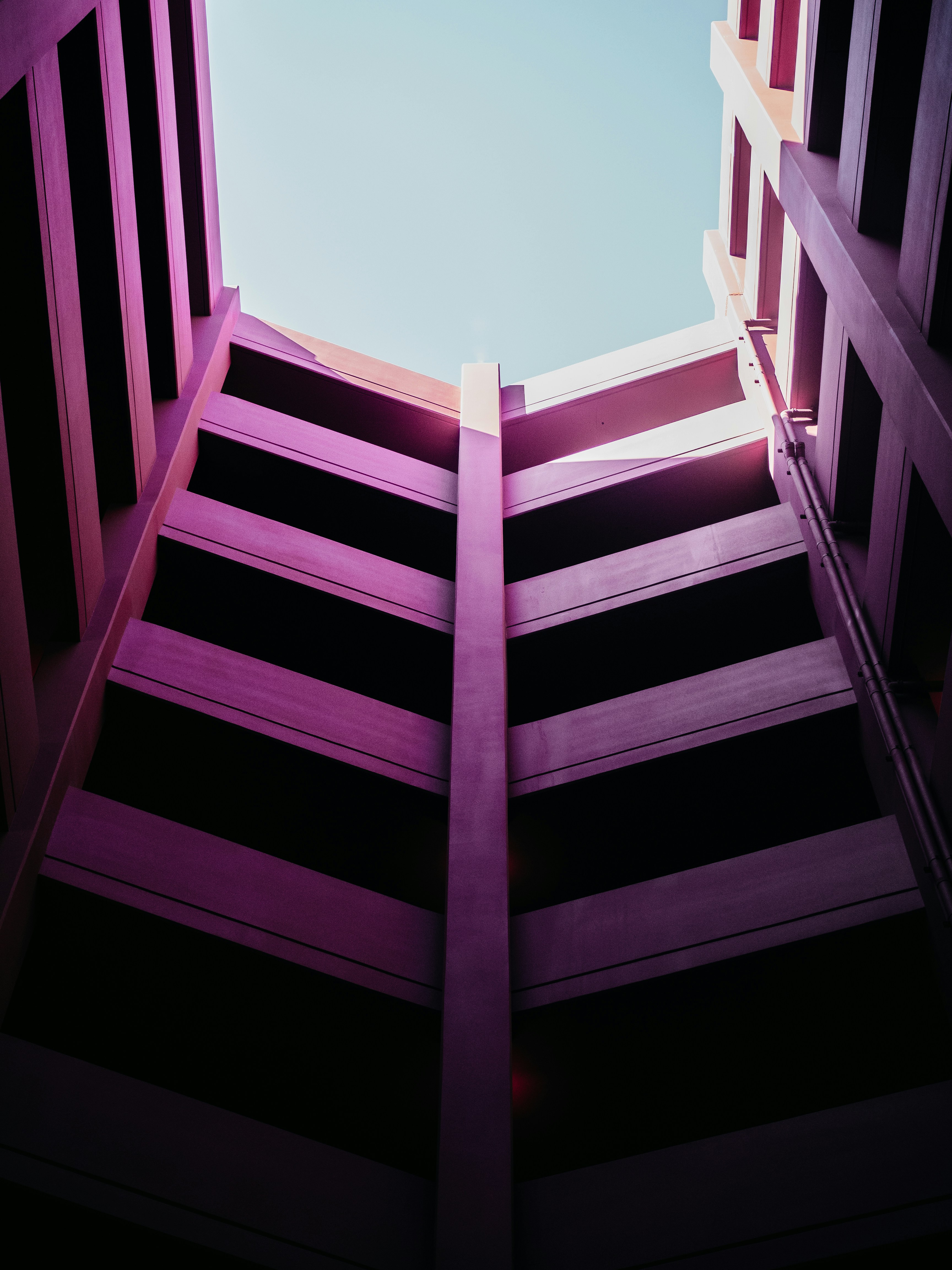 Looking up through a modern parking structure, showcasing geometric lines and contrasting colors against the sky.