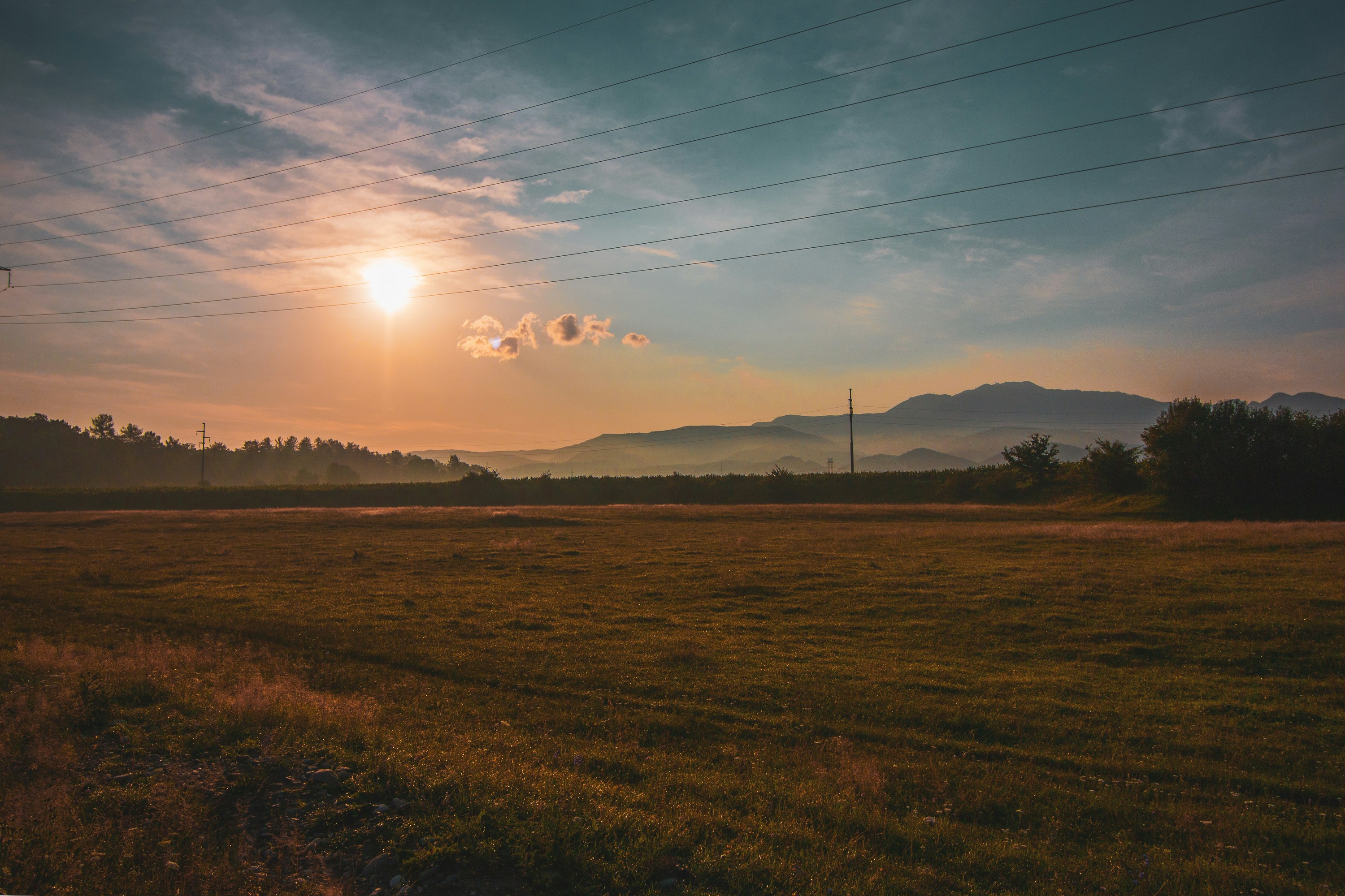 Low-angled Sunrise over Open Field with Distant Hills