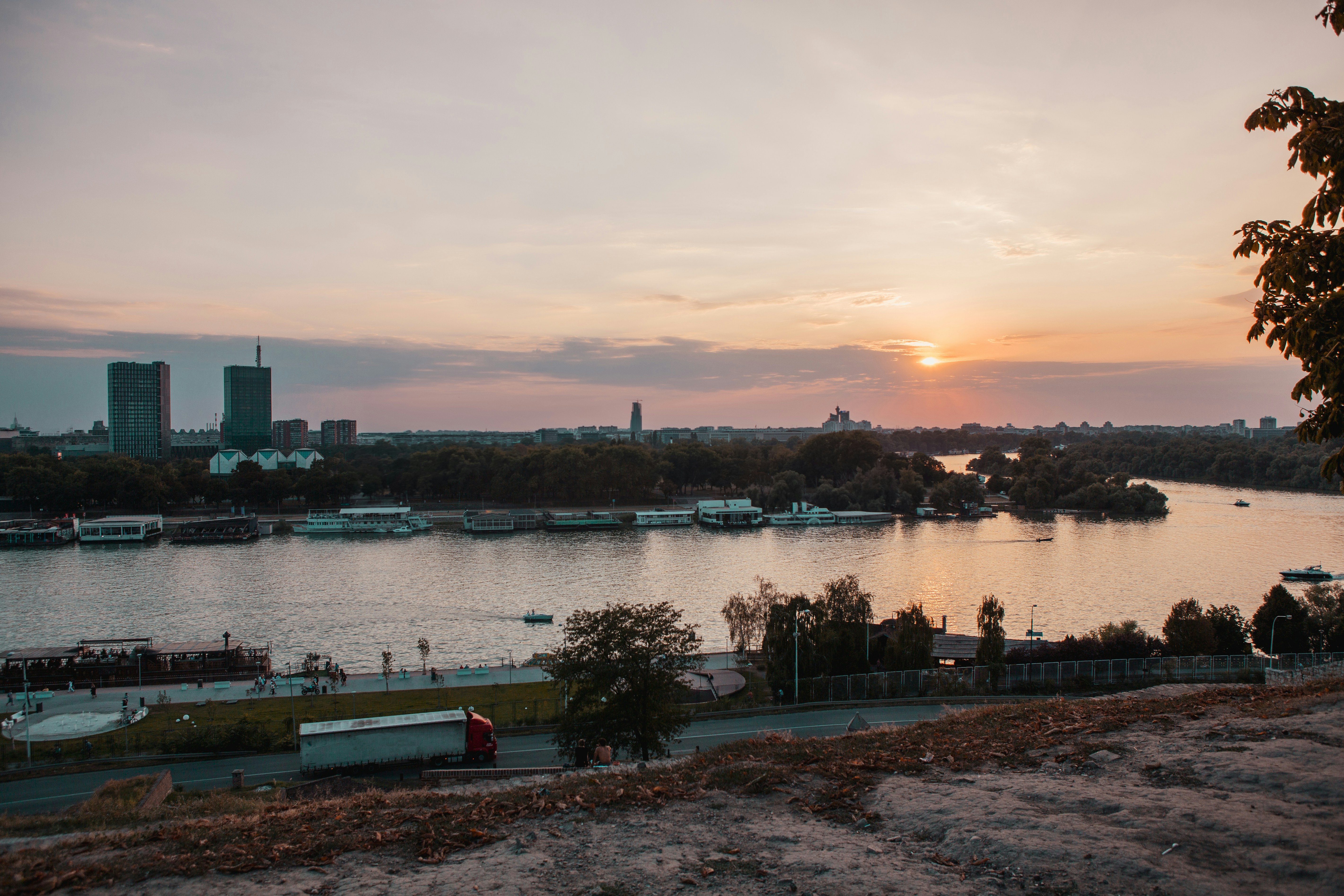 Tranquil river reflecting the warm hues of a sunset with city buildings silhouetted in the background.