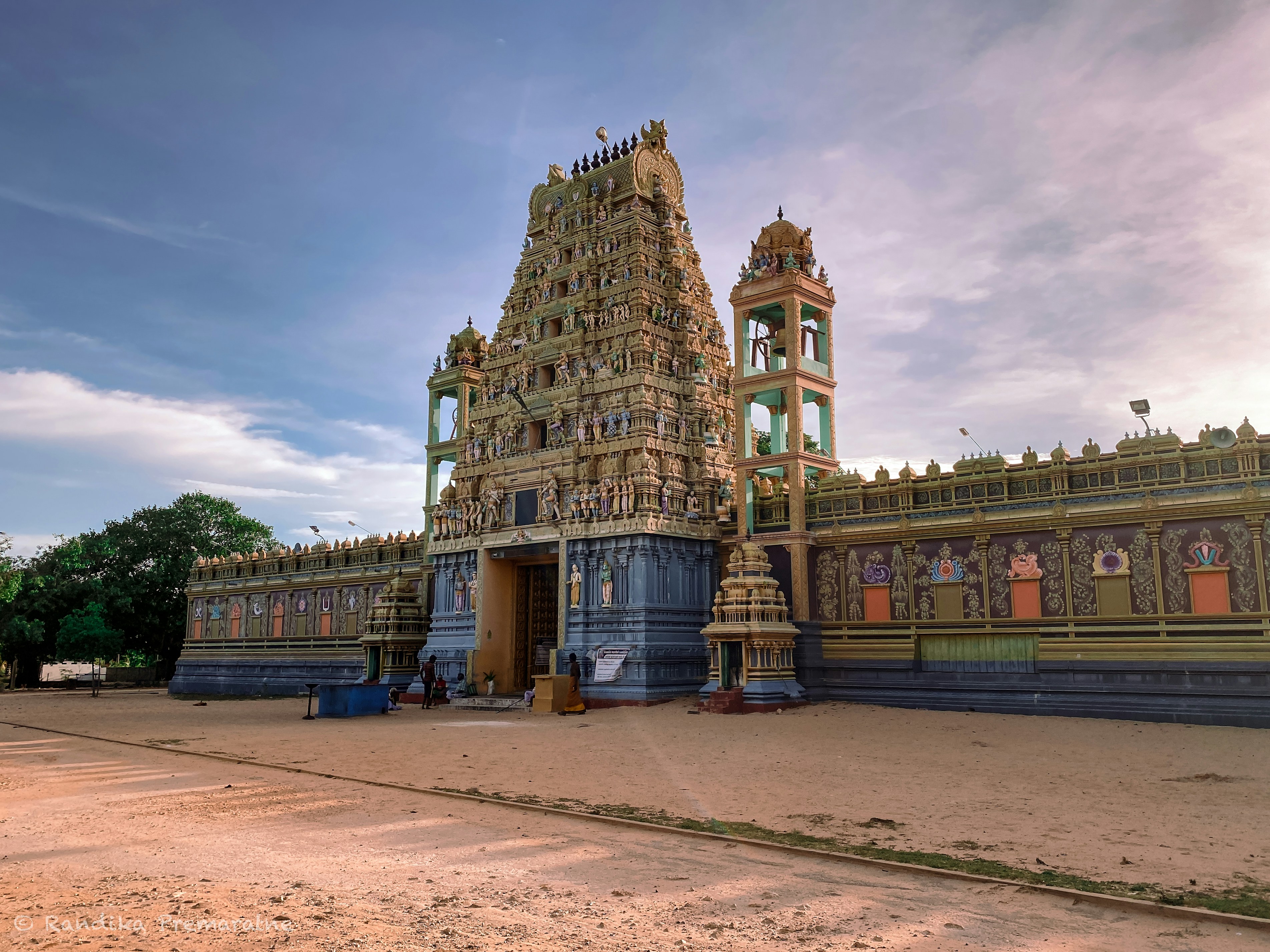 Intricately designed Hindu temple with vibrant colors and detailed carvings under a partly cloudy sky.