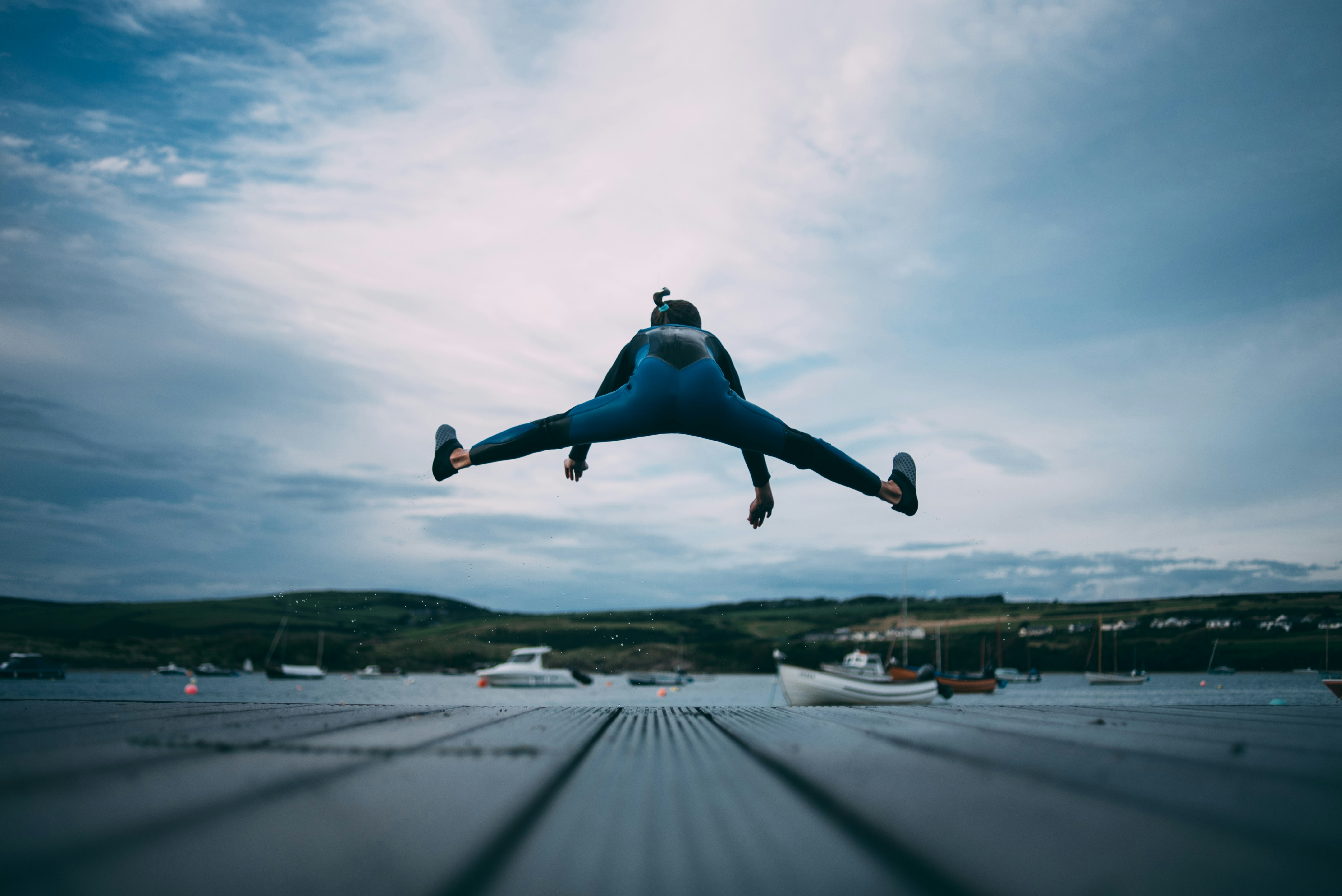 Midair Splash: A Leaping Figure Over a Quiet Marina