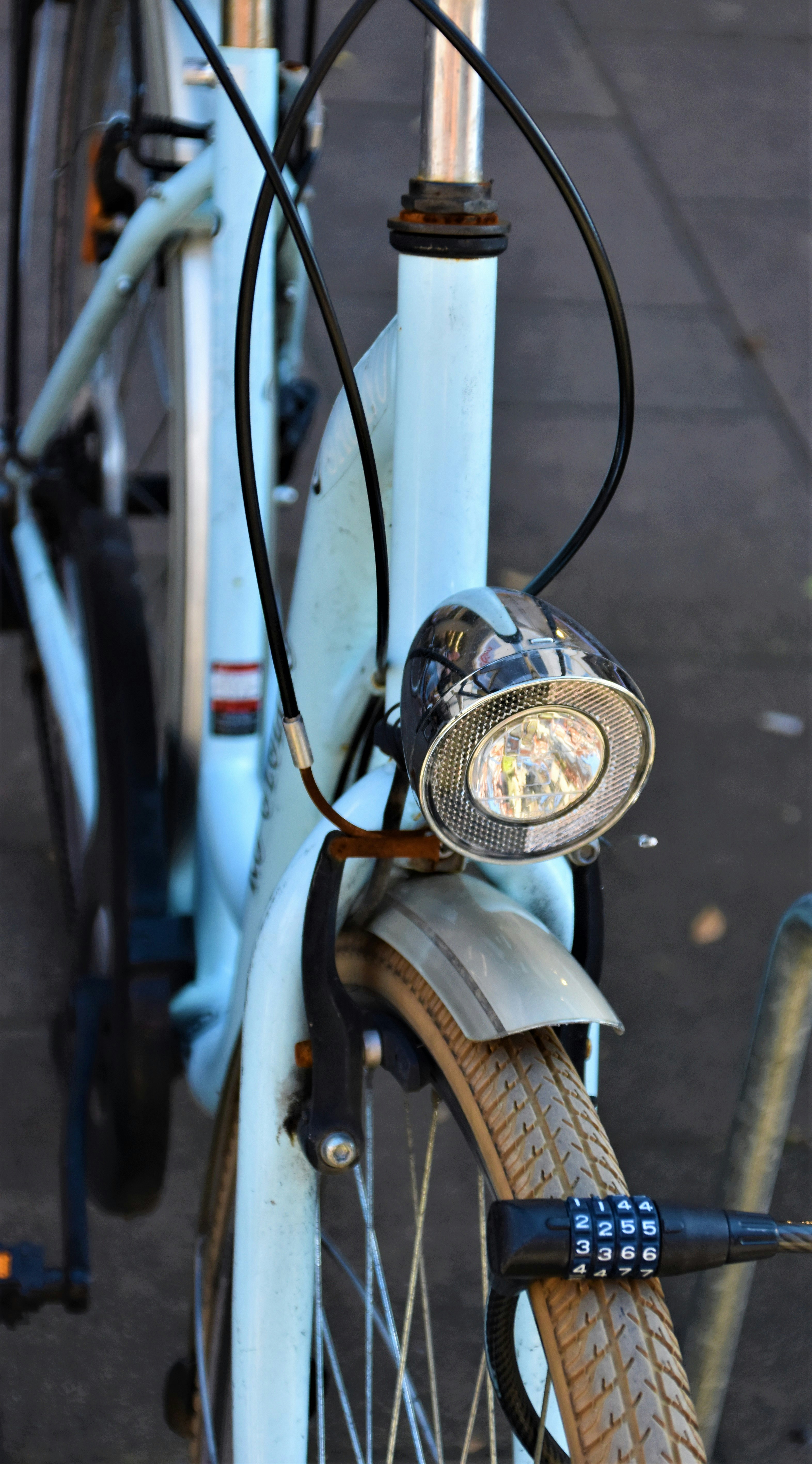 a blue bicycle is standing with an number lock in a town