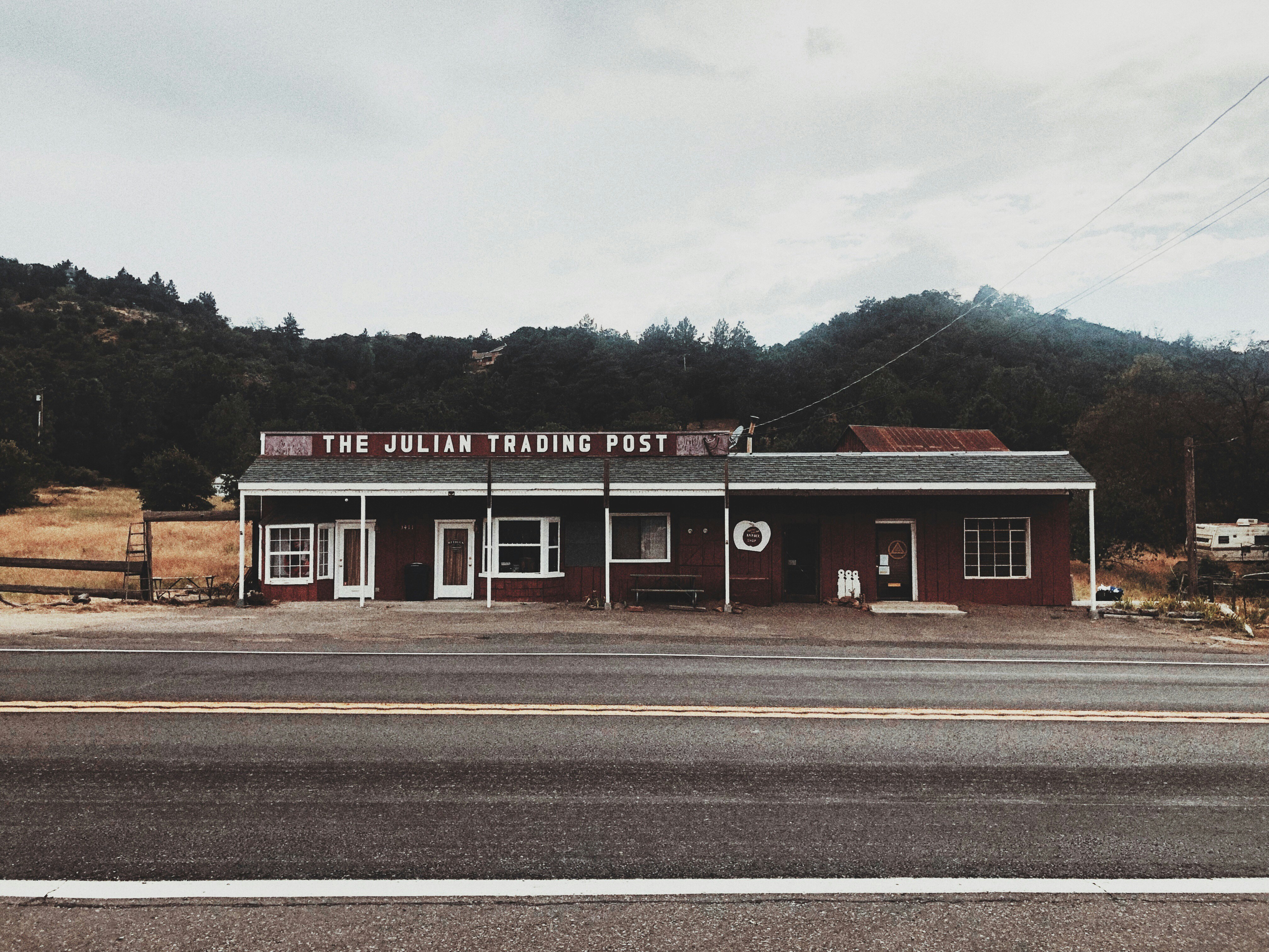 Rustic roadside building with a vintage feel, set against a backdrop of rolling hills and a cloudy sky.