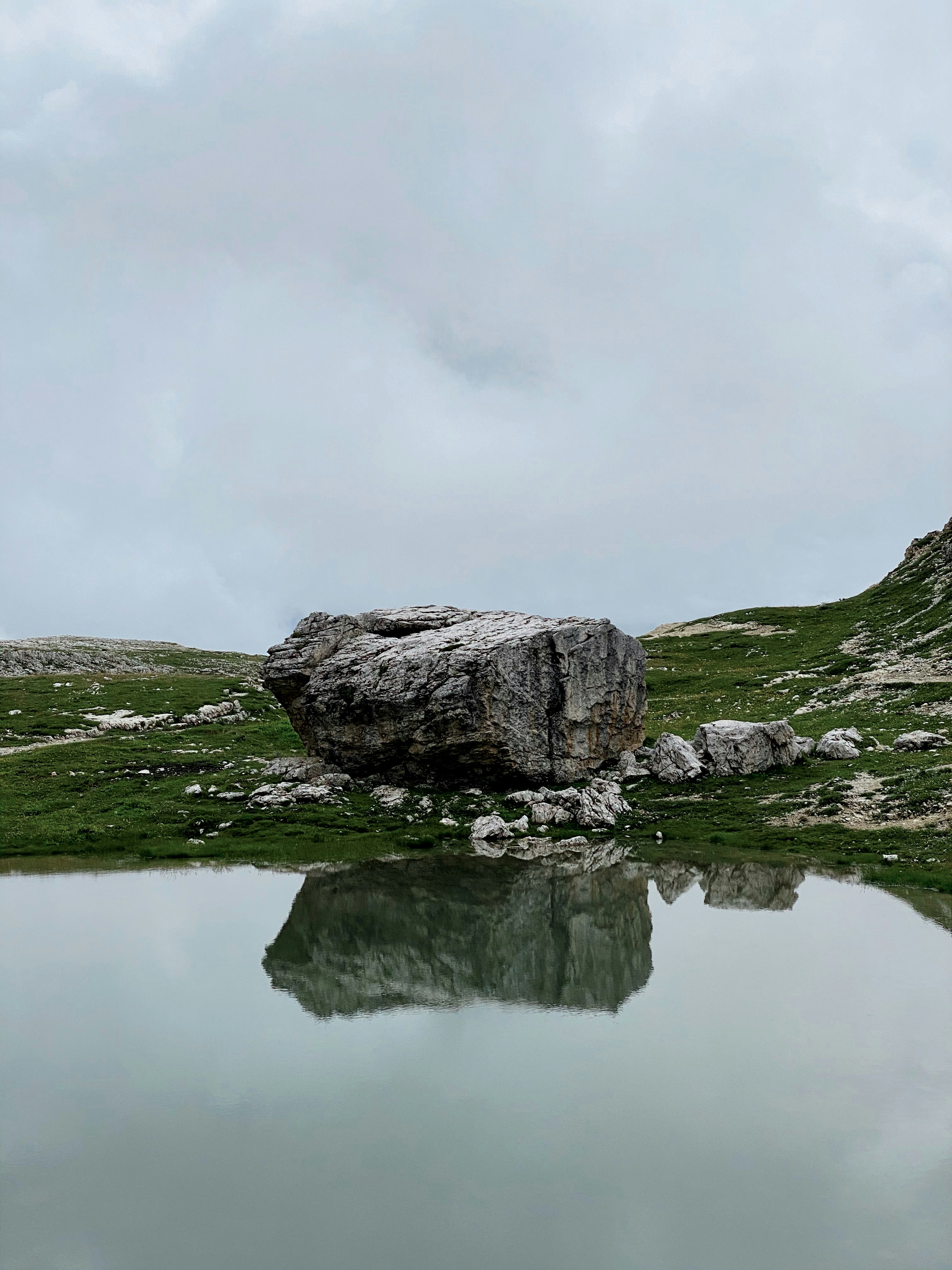 Gray rock formation on green grass field near body of water during ...