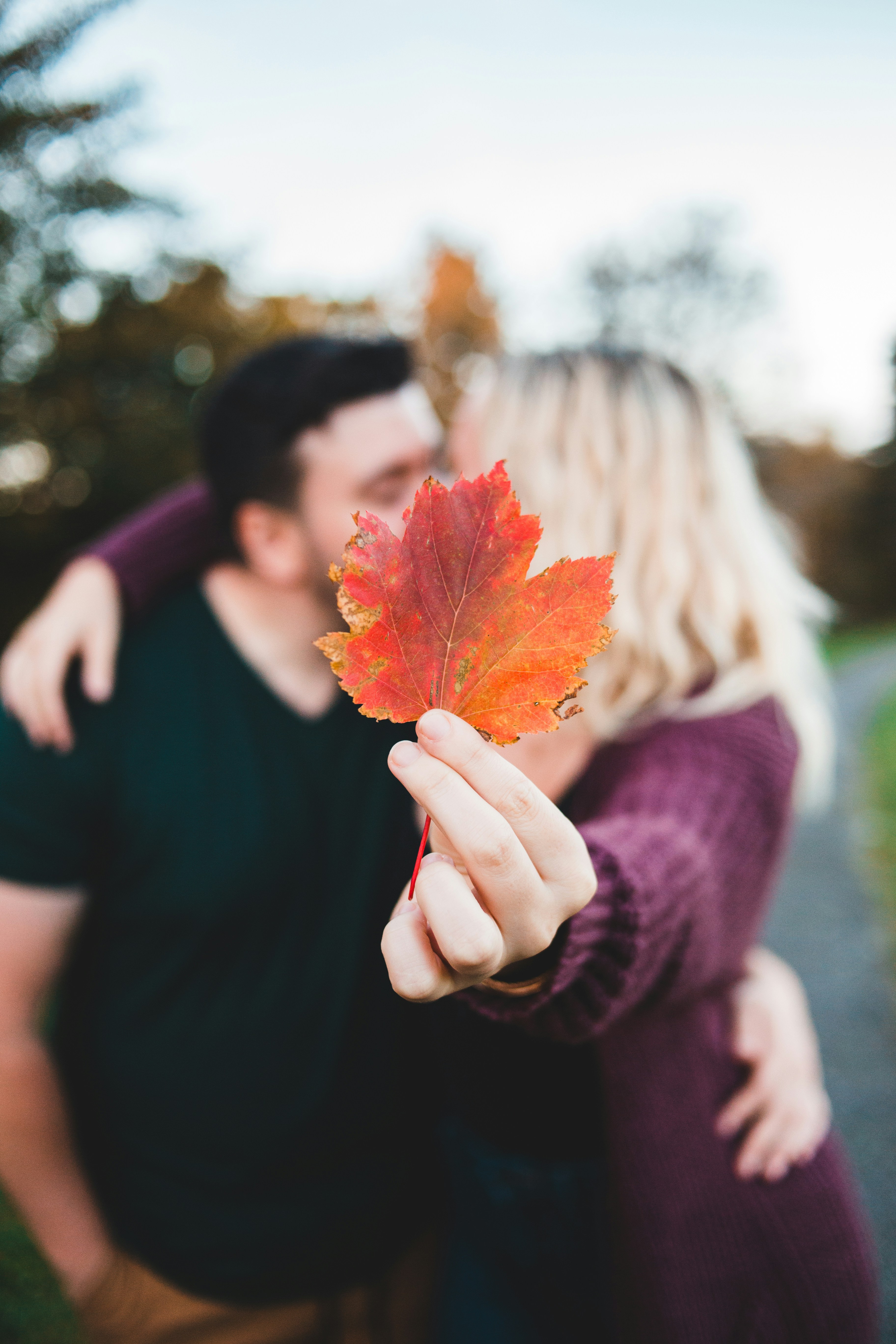 Autumn Leaf Focus: A Couple Blurred in the Background Shares a Moment