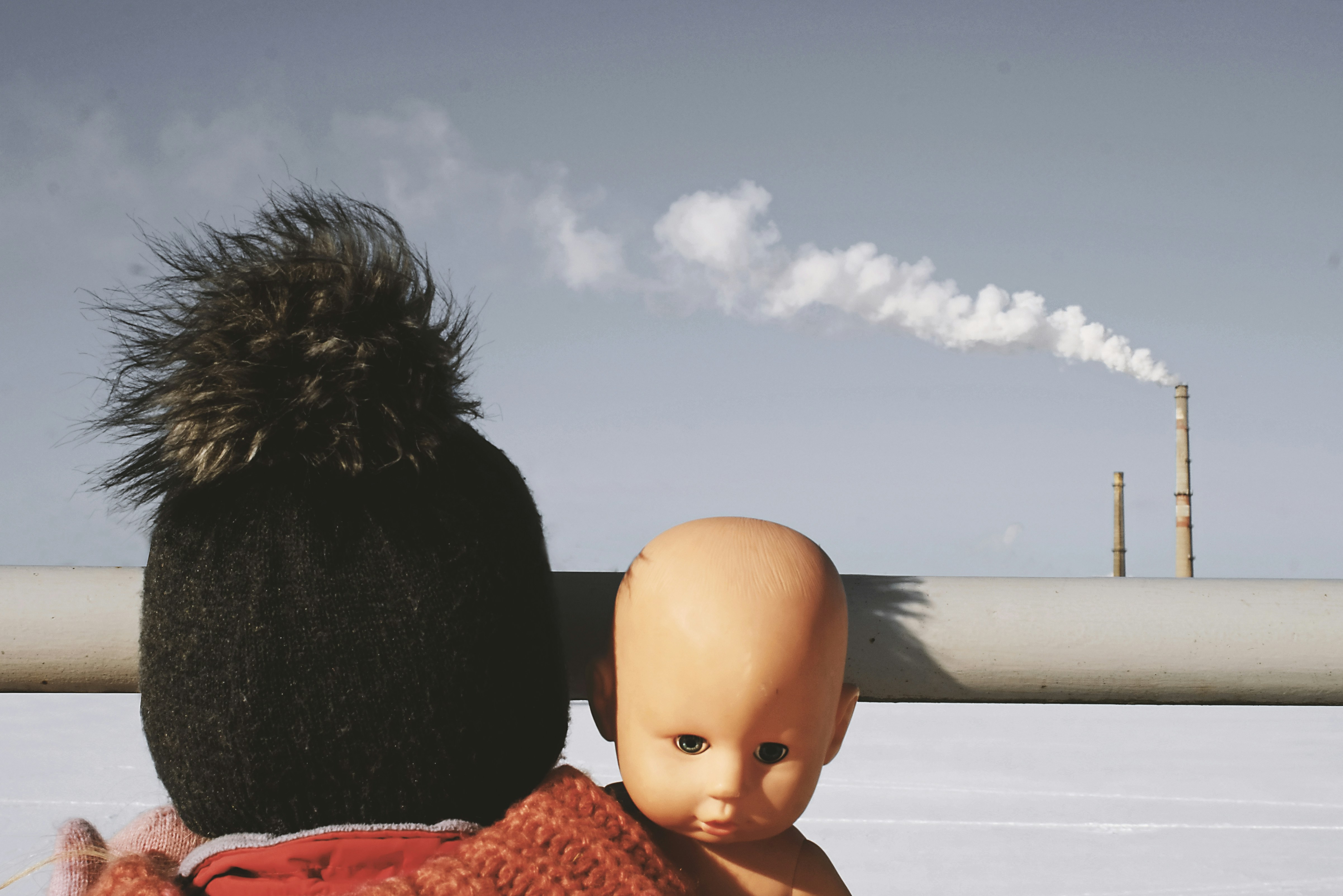 Two Voices at the Panel: A Child’s Head Beside an Adult Backlit by Industrial Skyline