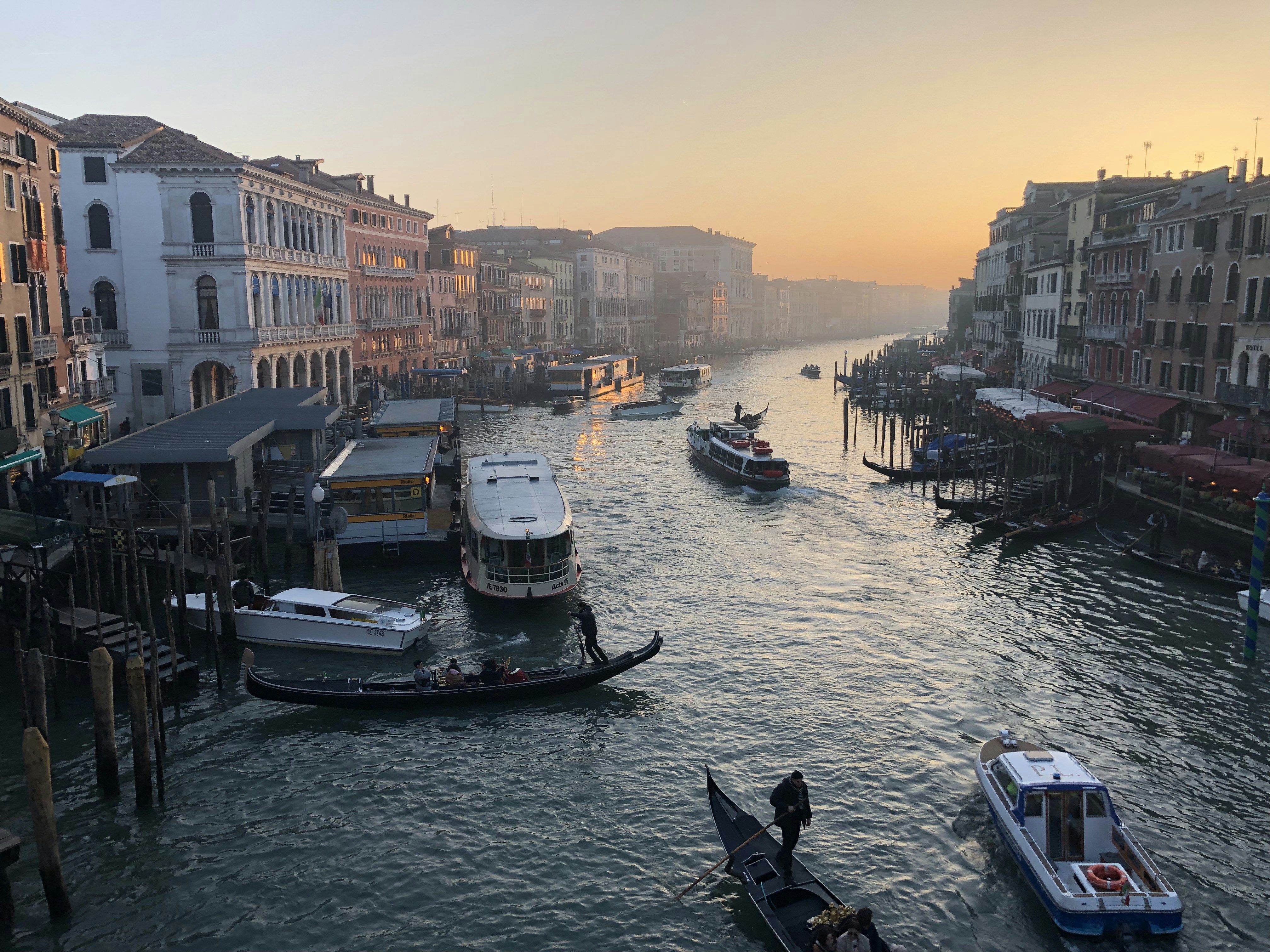 Gondolas and boats navigate the serene canals of Venice at dawn, surrounded by historic architecture and soft morning light.
