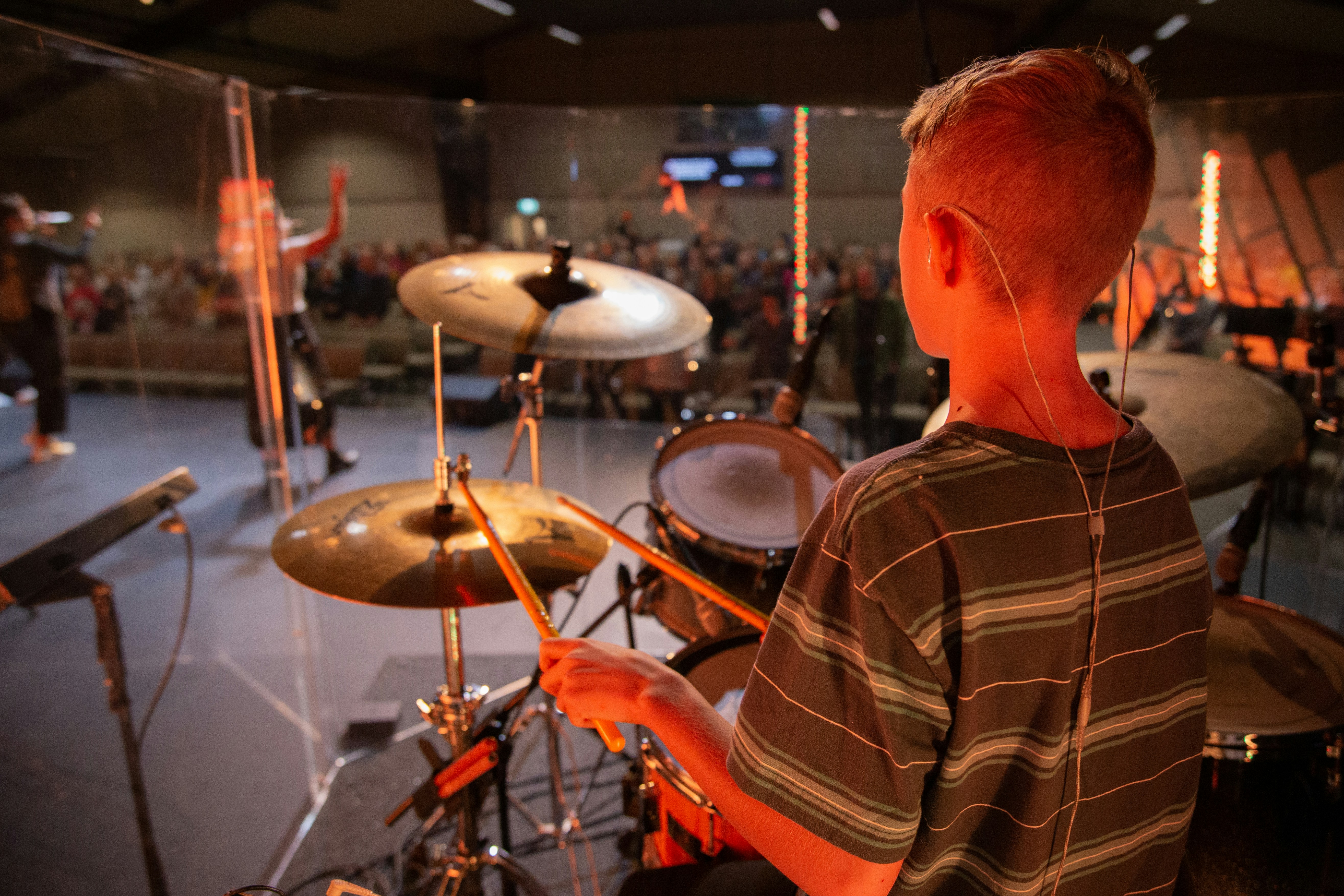 Backstage Beat: A Young Drummer in the Warm Stage Glow
