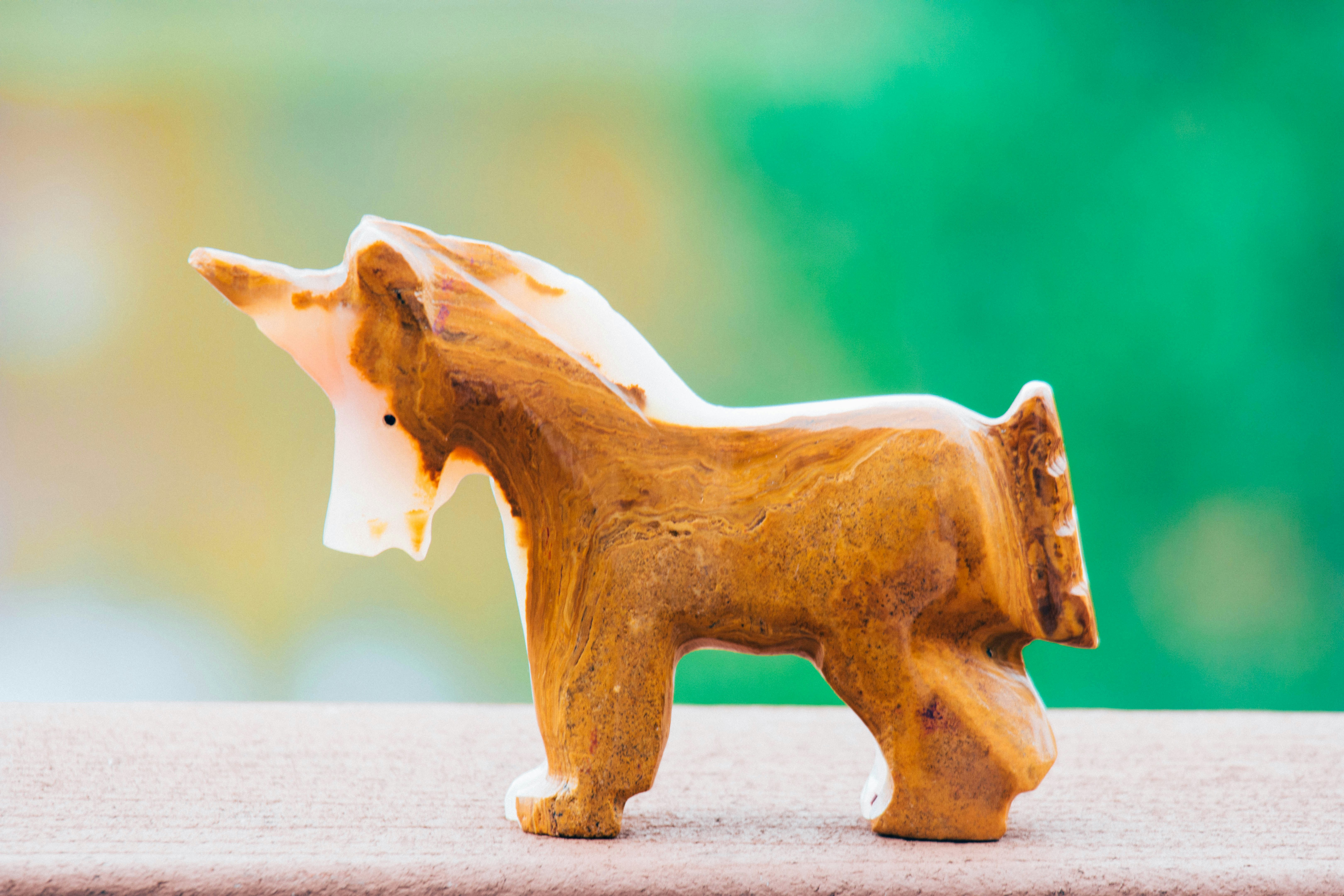 Intricately carved unicorn figurine showcasing a blend of earthy tones against a soft, blurred background.