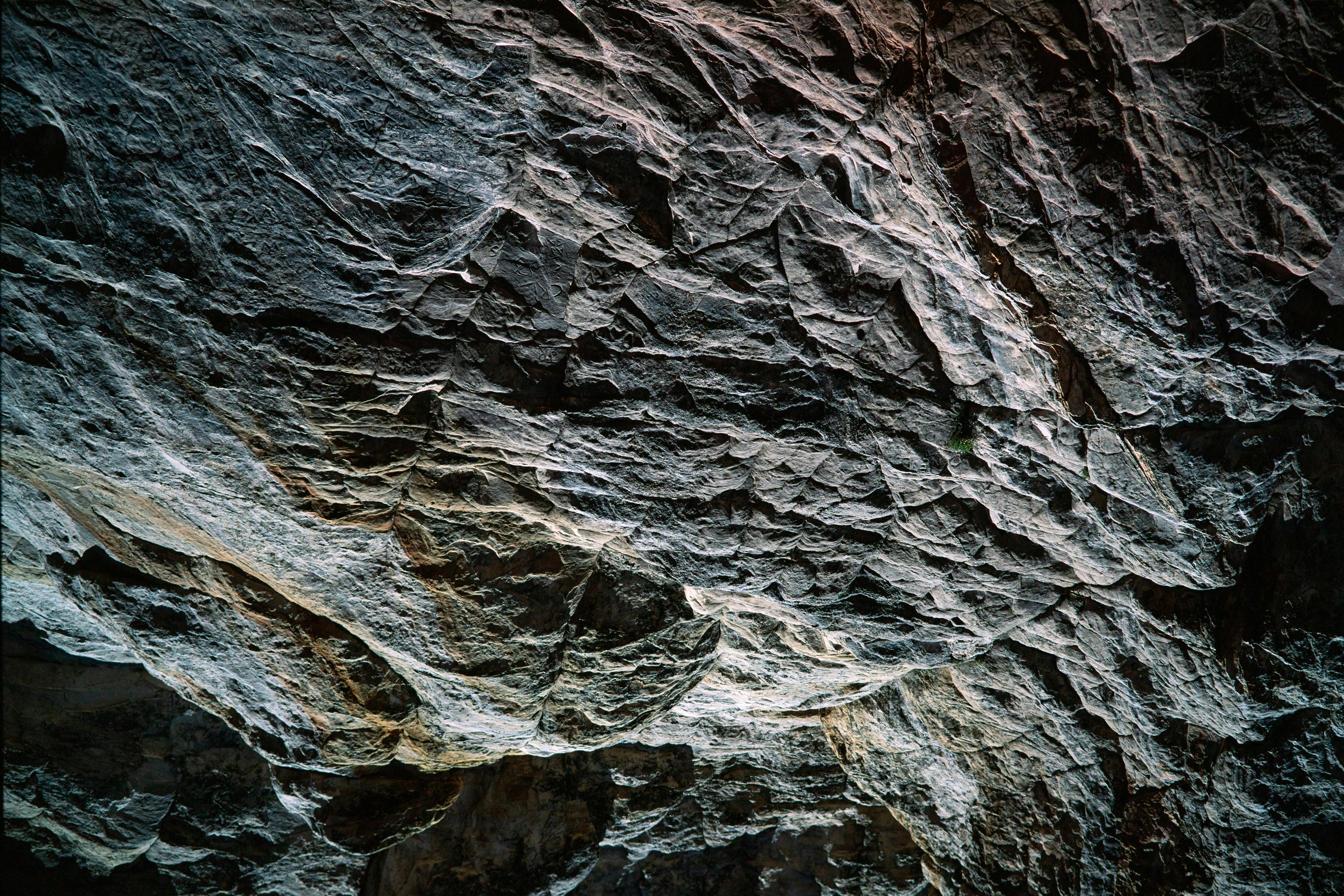 Intricate textures of a rocky cave ceiling illuminated by soft light, revealing layers of geological history.