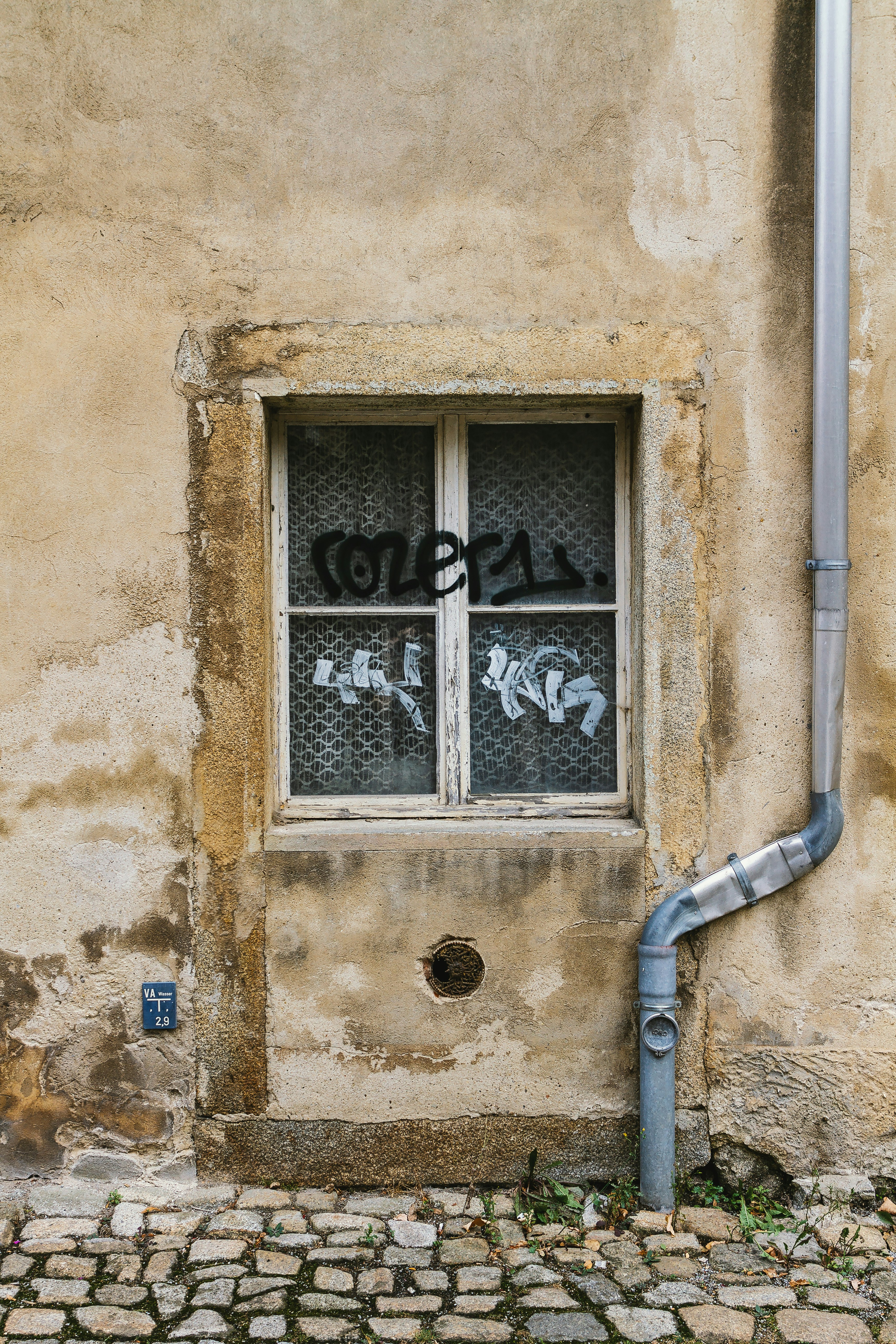 Weathered Window Graffiti and a Winding Downspout